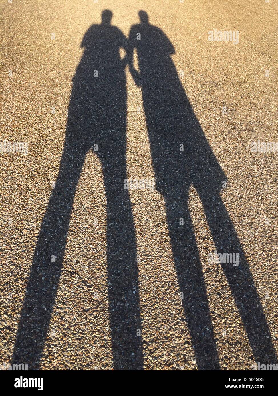 The elongated shadows of two people standing on a gravel road Stock ...