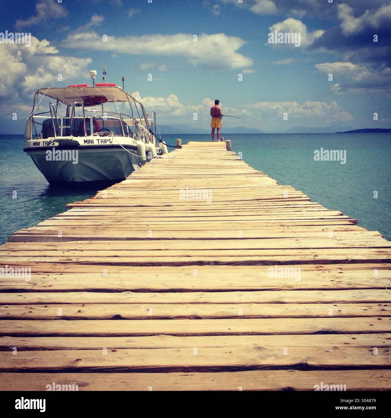 Man fishing at end of wooden walkway Stock Photo - Alamy