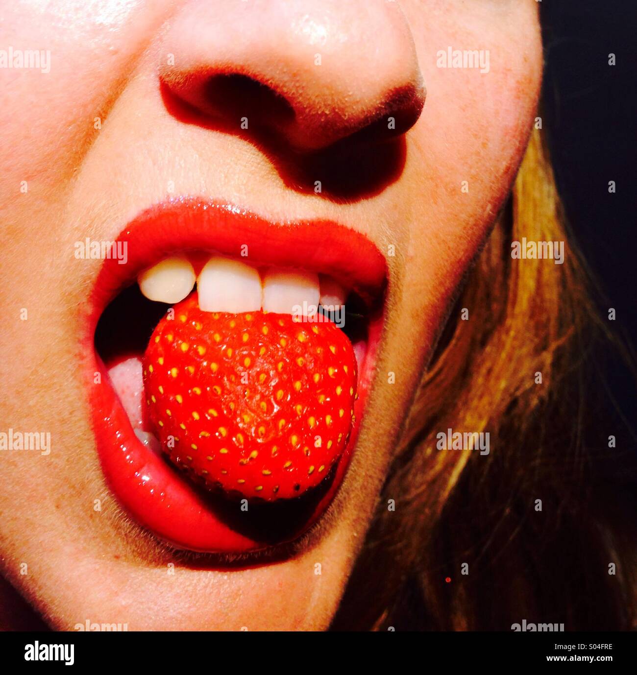 Strawberry between red lips Stock Photo - Alamy