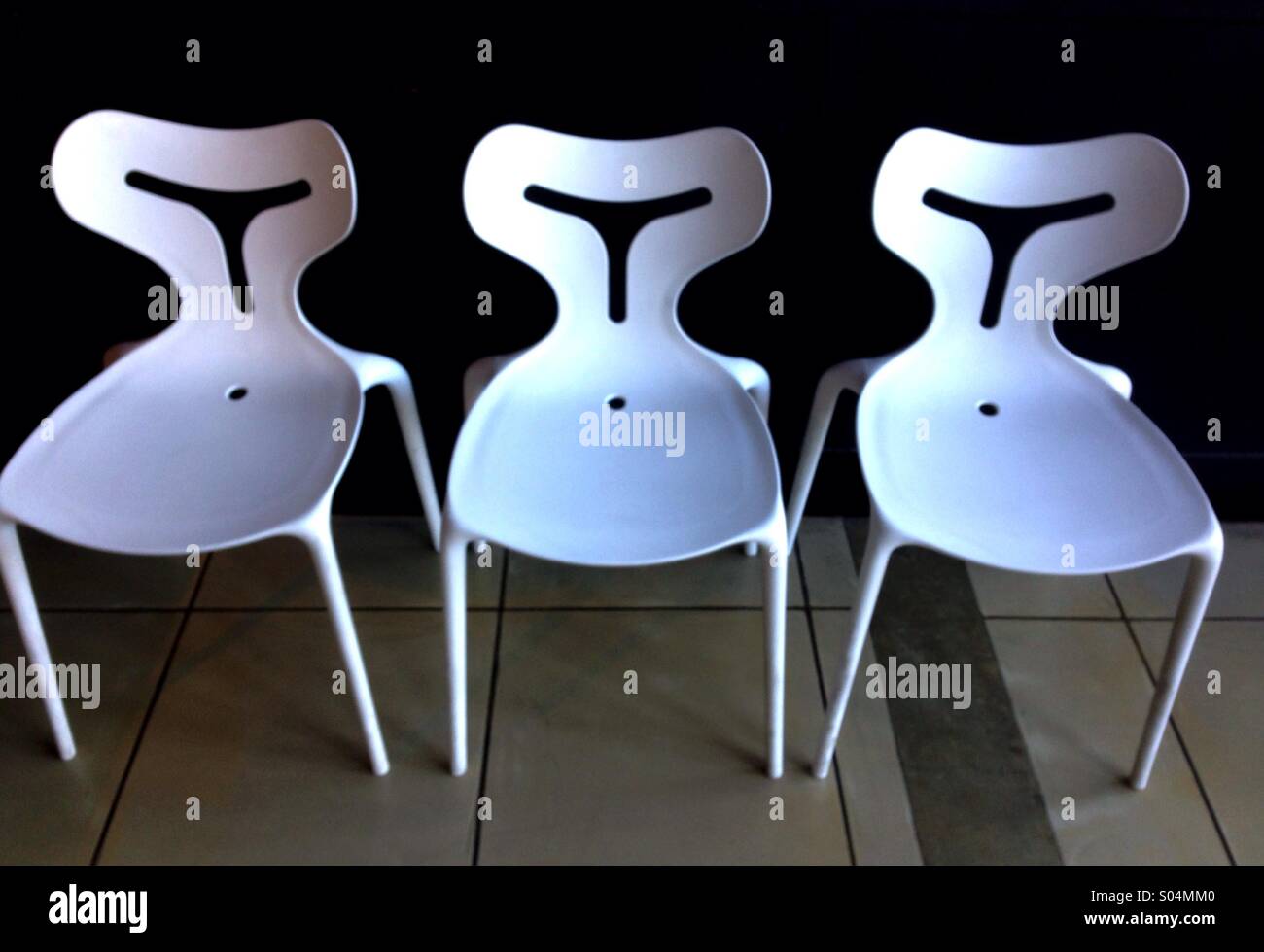 Three white chairs in a row Stock Photo - Alamy