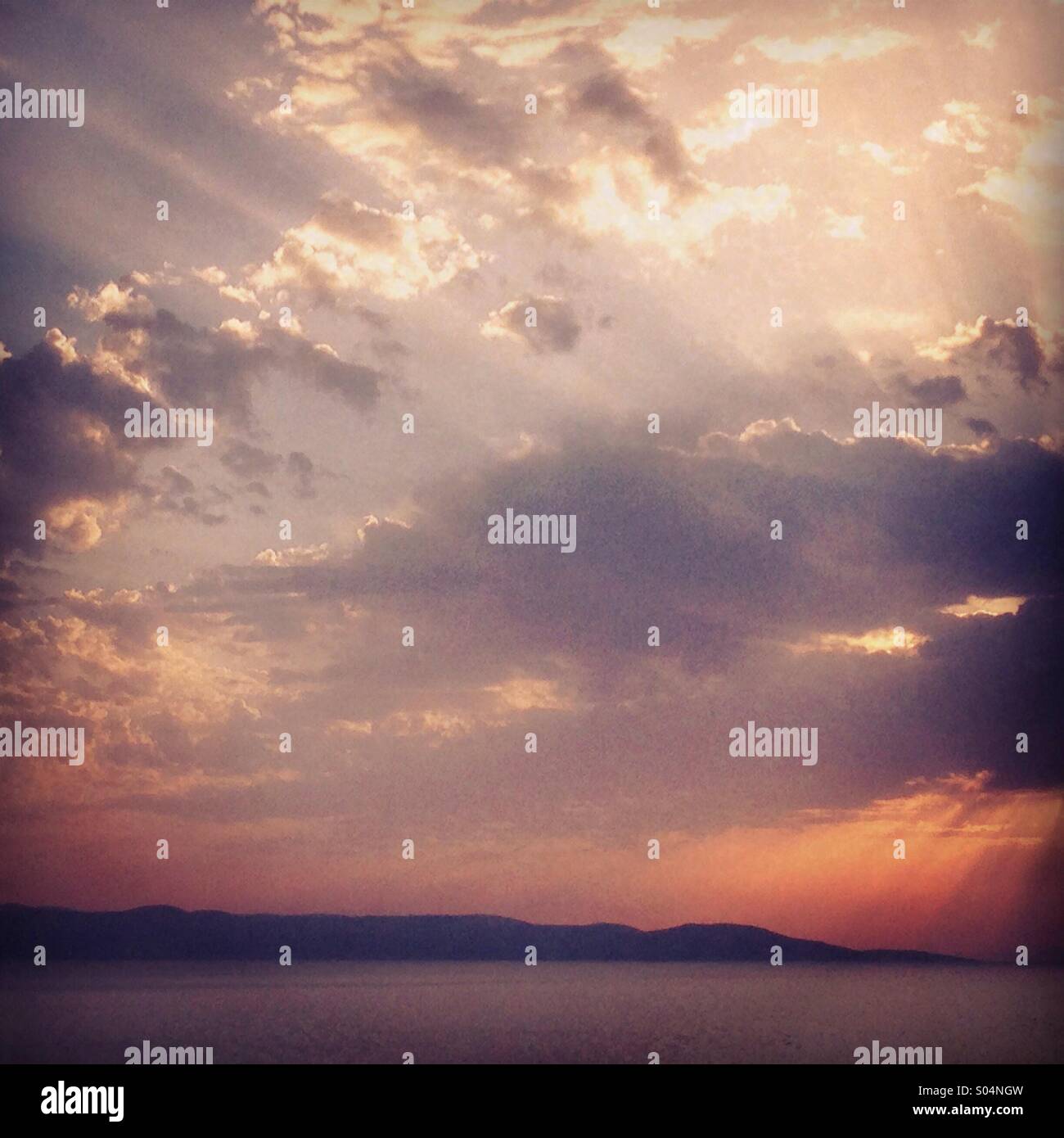 Sunset at sea with sun rays through clouds Stock Photo - Alamy