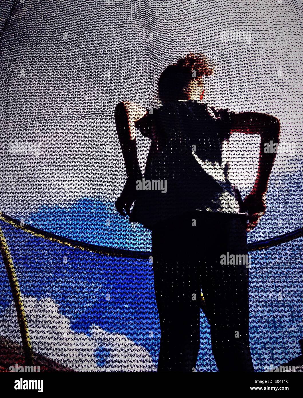 Girl jumping on trampoline seen through safety net Stock Photo - Alamy