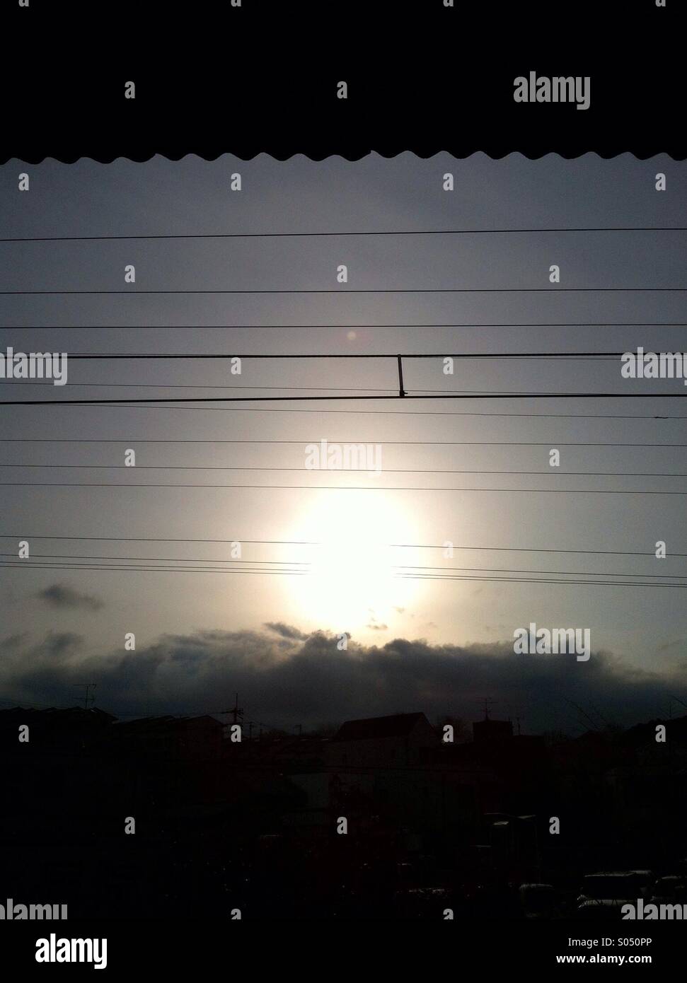 Sun rising above cloud and electric wires. Juxtaposition of natural ...