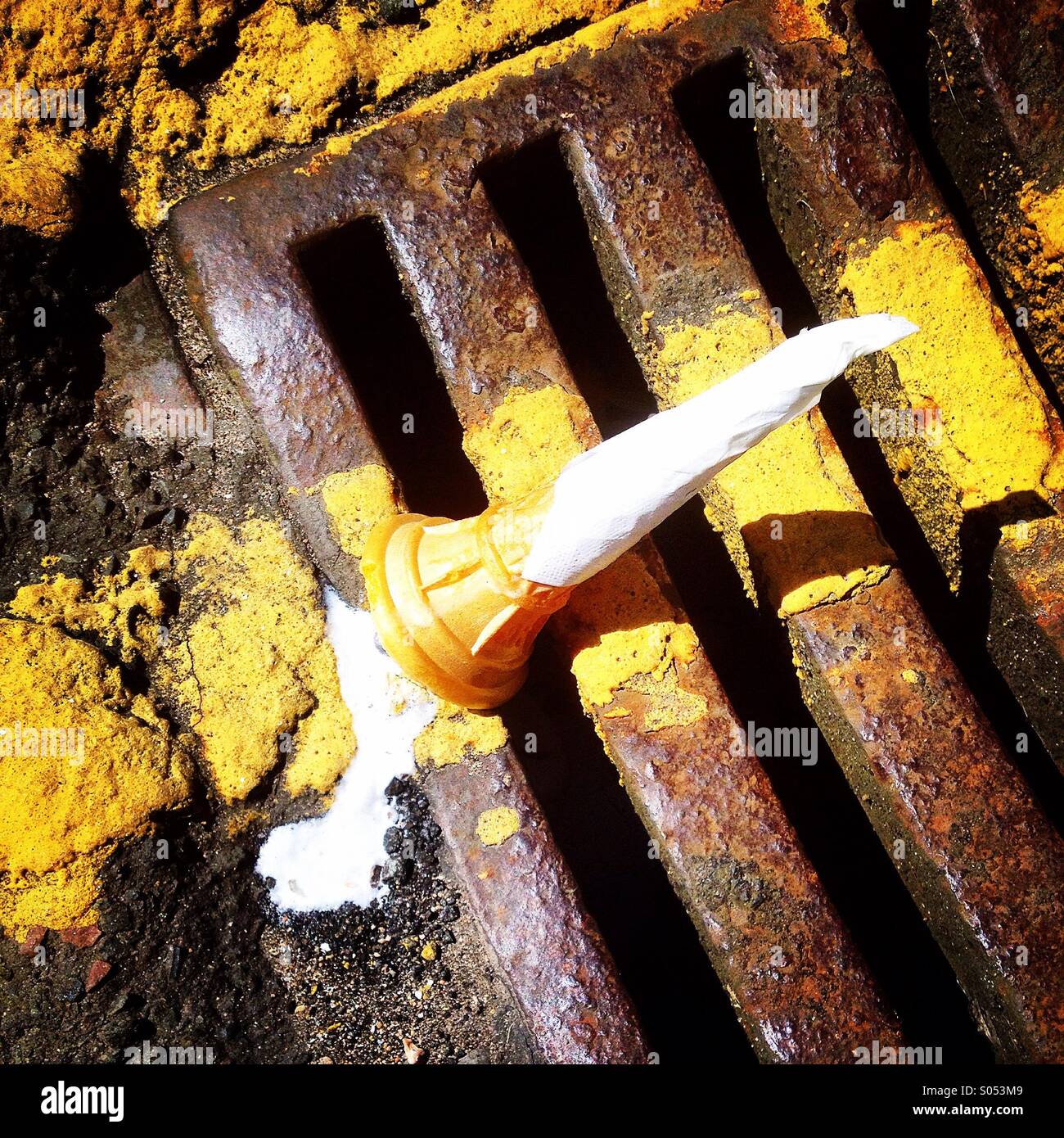 Ice cream dropped onto yellow line over grating at side of the road ...