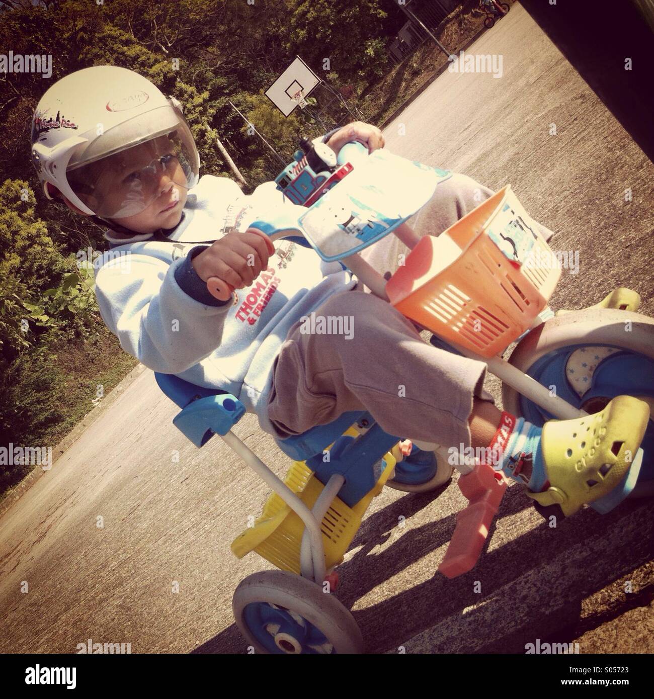 Grumpy little boy doing motorcycle toy with helmet on his head Stock ...