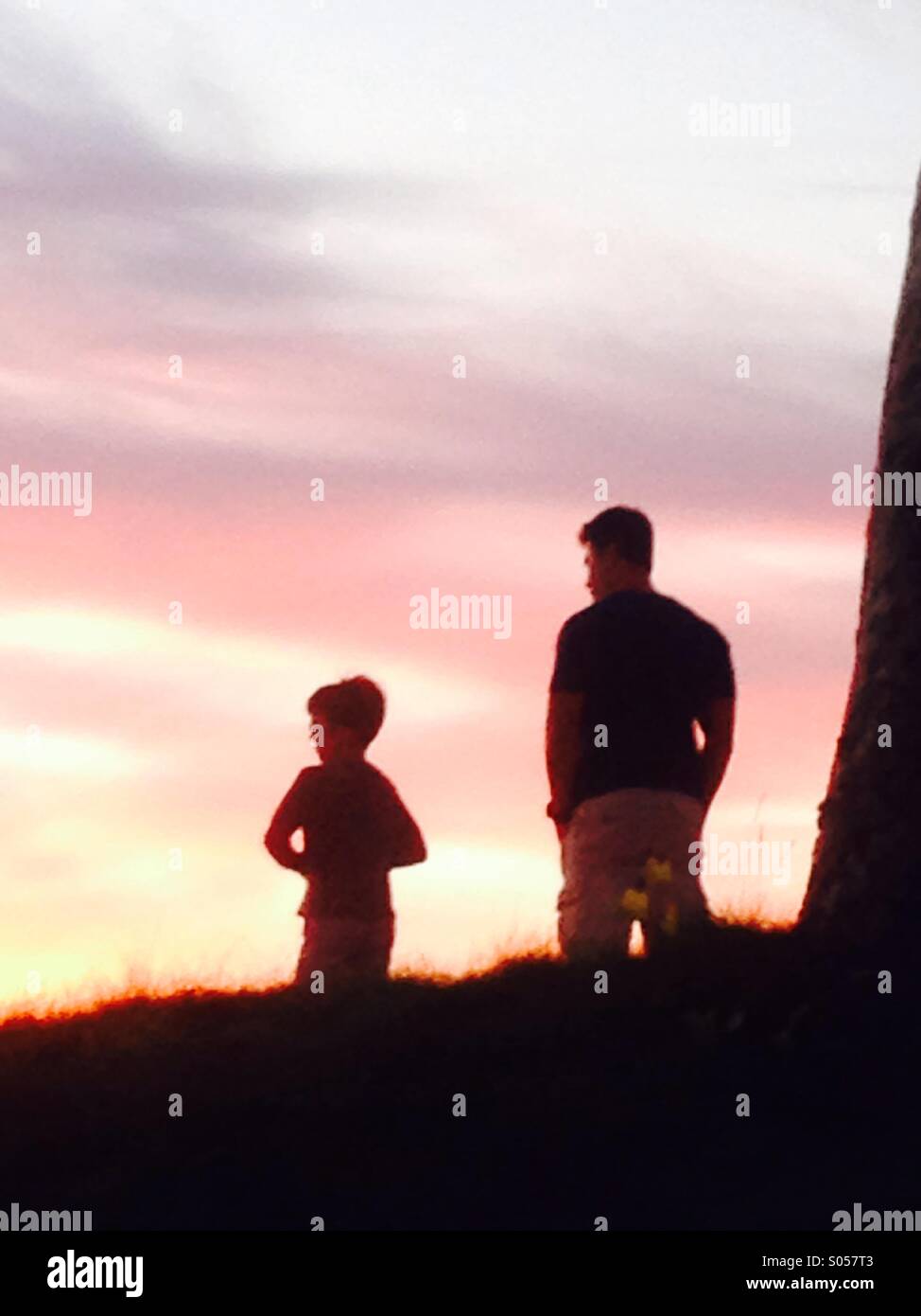Father and son looking at sunset Stock Photo - Alamy