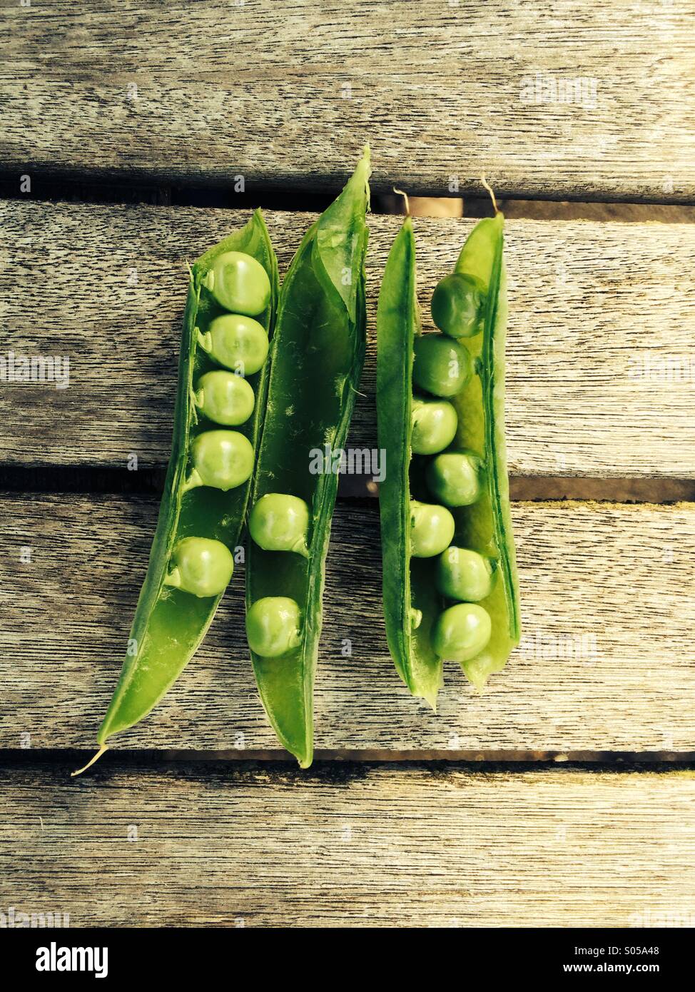 Peas in a pod on a wooden table Stock Photo - Alamy