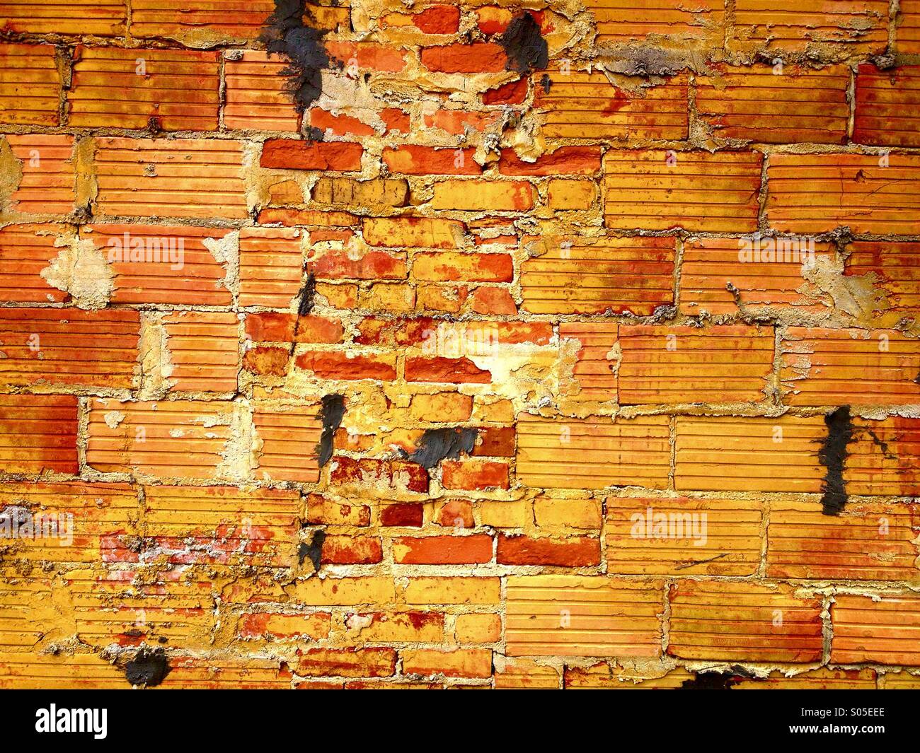 Detail of a colorful orange and yellow brick wall that has been ...