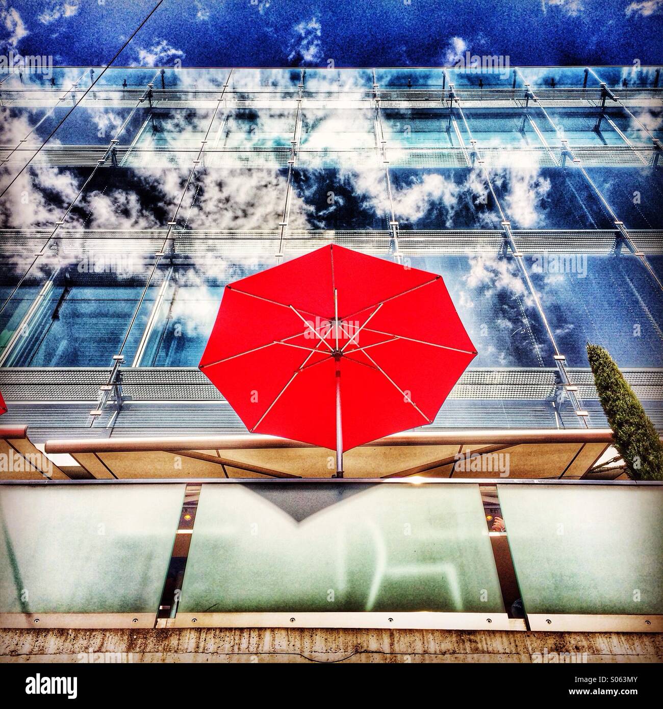 Red parasol against glass facade with reflected clouds Stock Photo - Alamy
