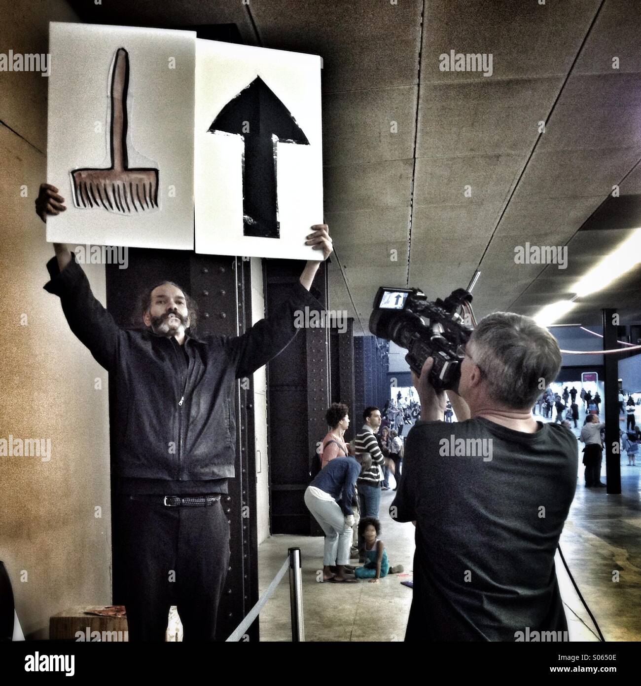 Man holding symbolic images whilst other man films him - a surreal ...