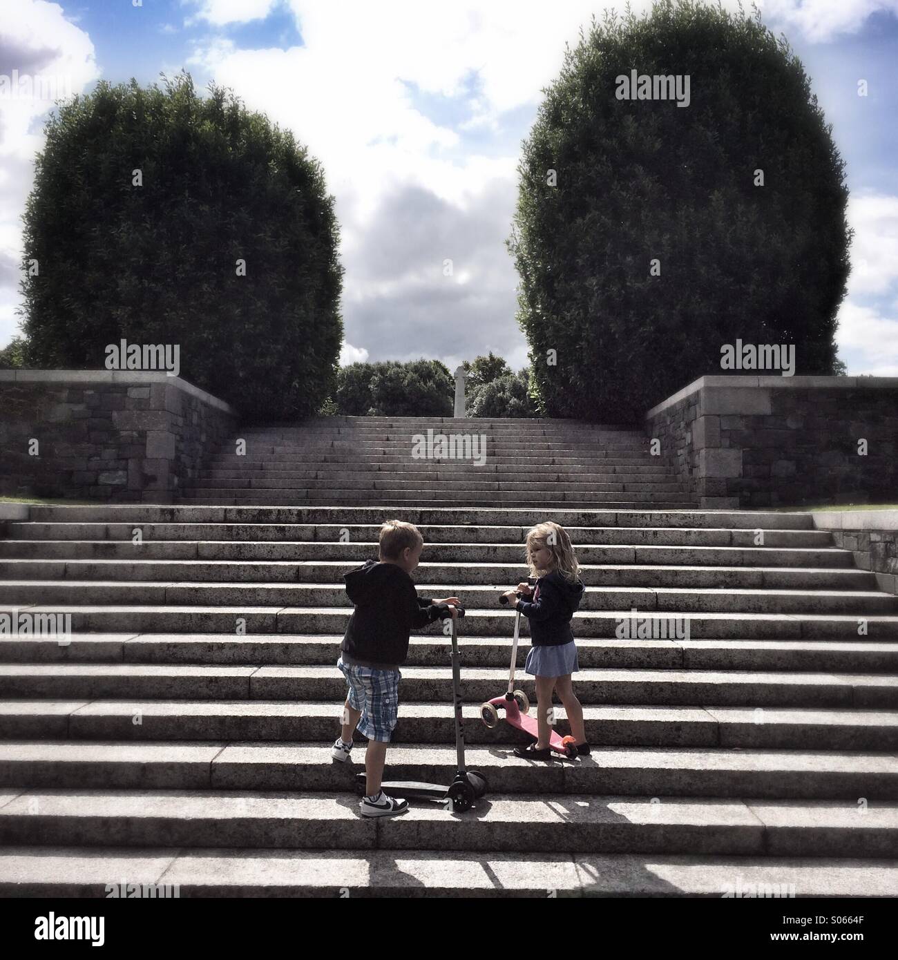 Two small children climbing steps with scooters Stock Photo - Alamy