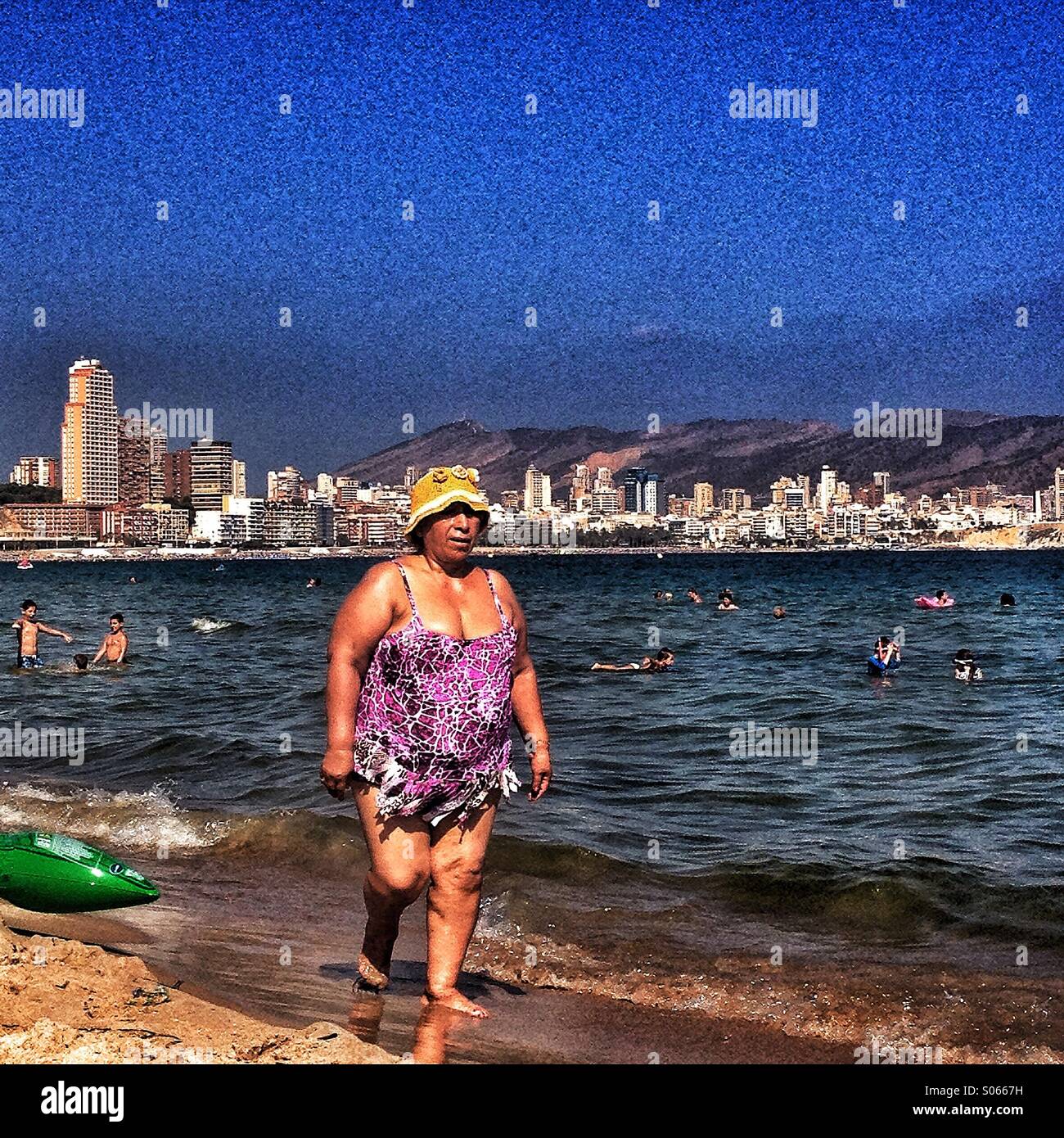Woman walking along a beach with Benidorm in the background Stock Photo ...