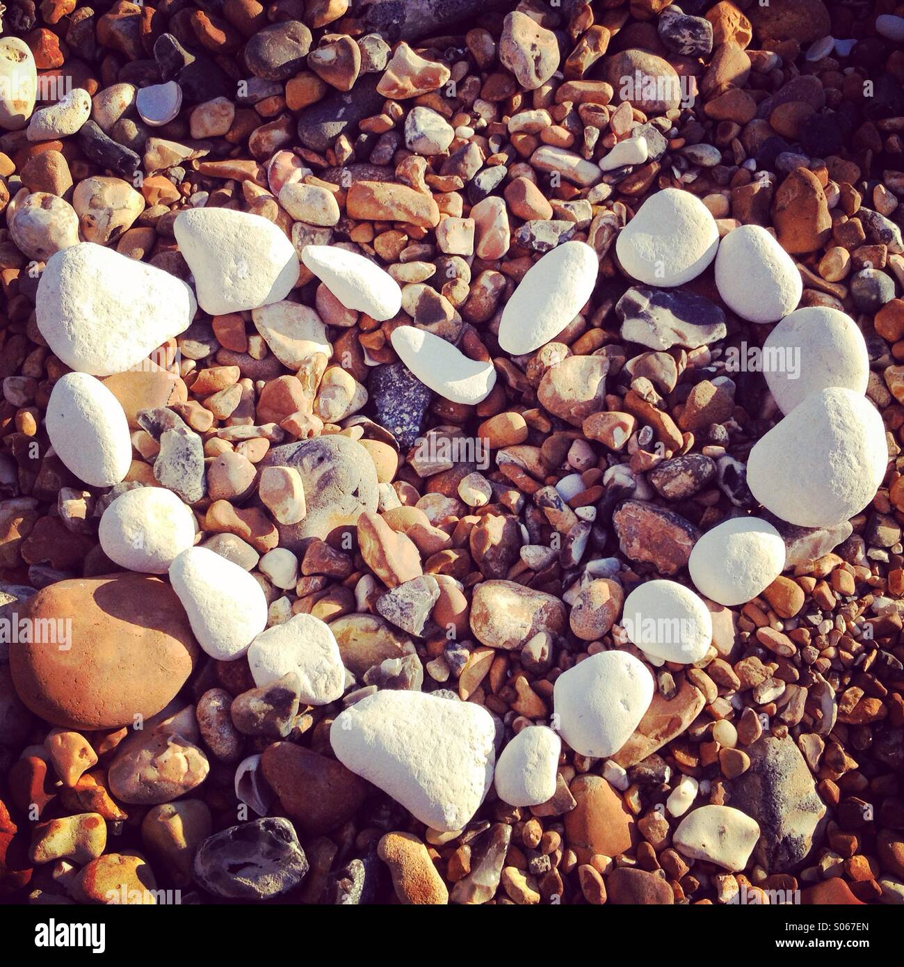 White pebble heart on pebble beach Stock Photo - Alamy