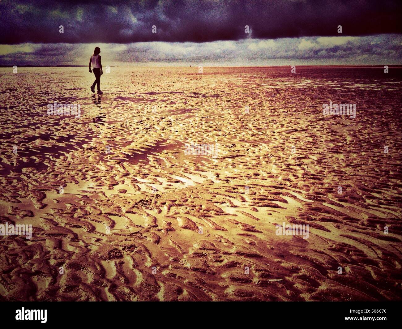 Young girl walking alone on empty beach Stock Photo - Alamy