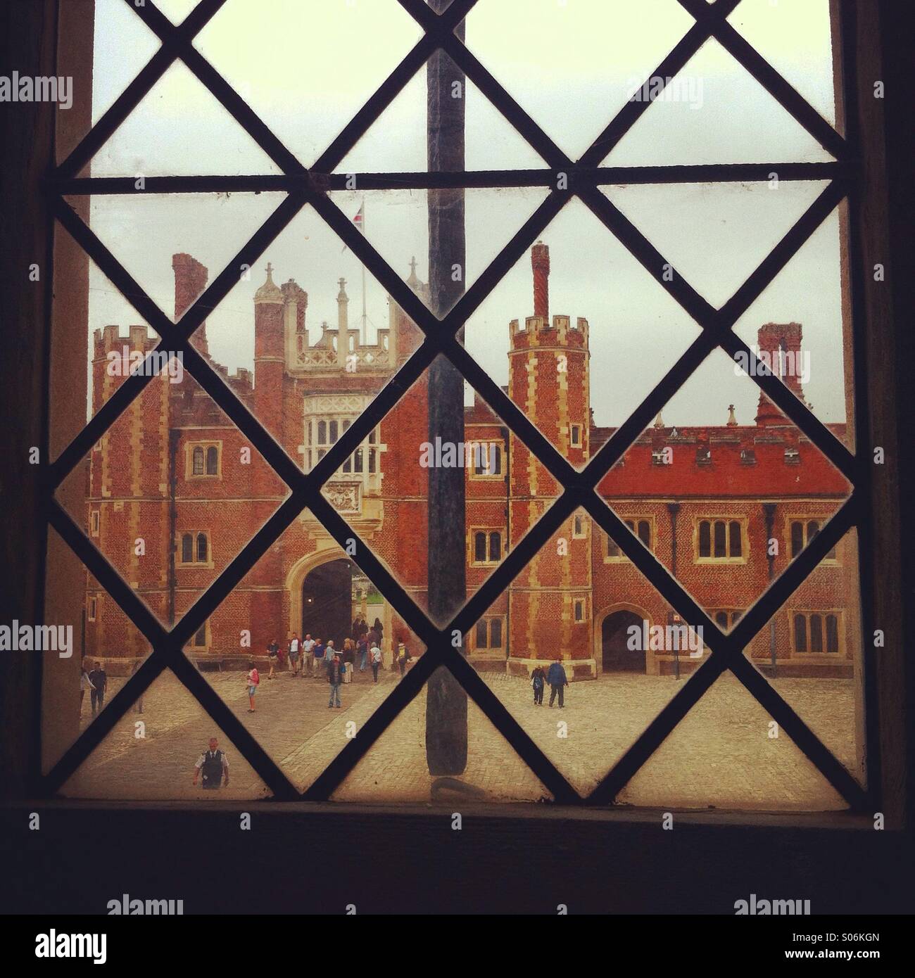 View of base court through a leaded window at Hampton Court Palace ...
