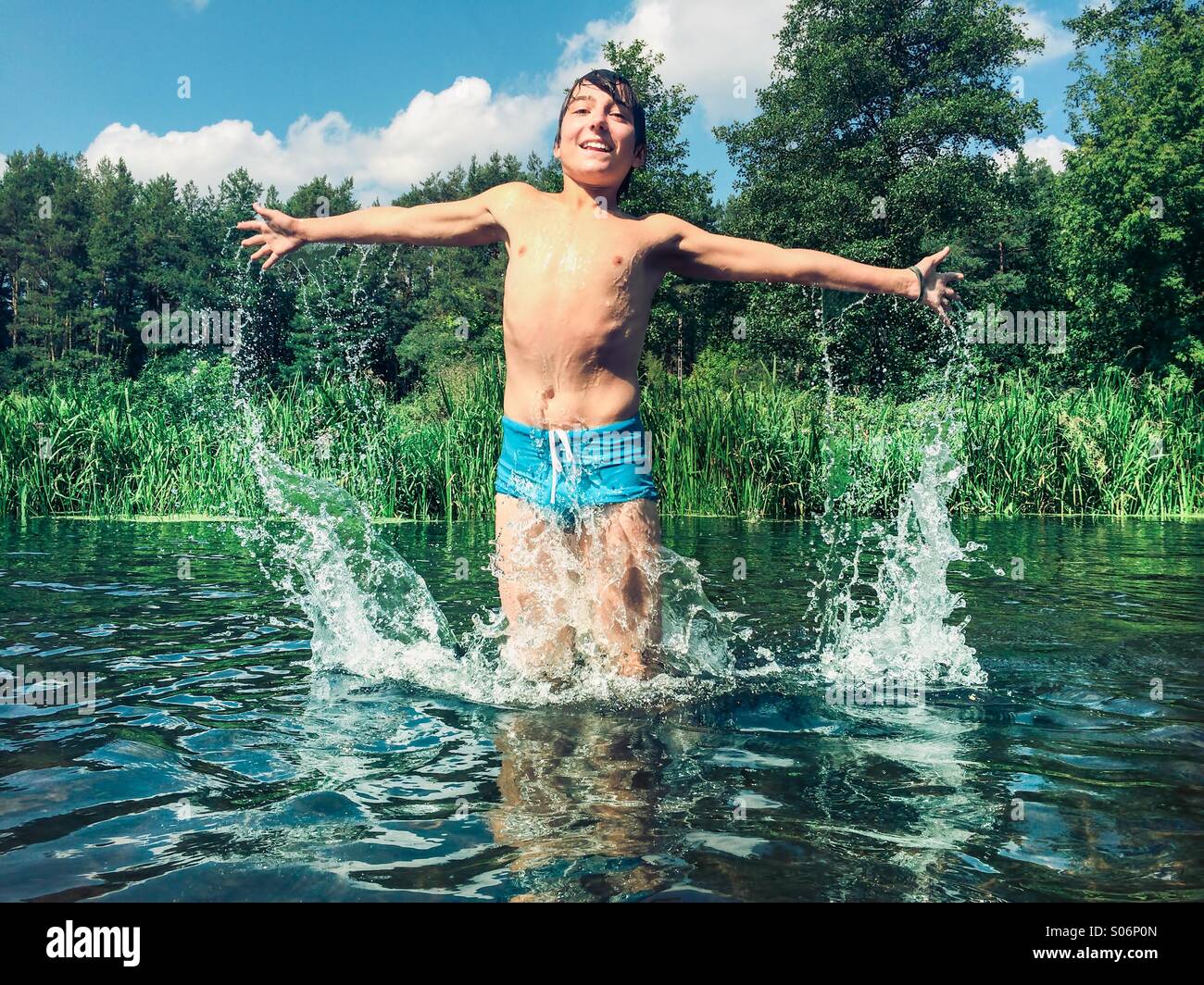 Young boy splashing in the river Stock Photo - Alamy