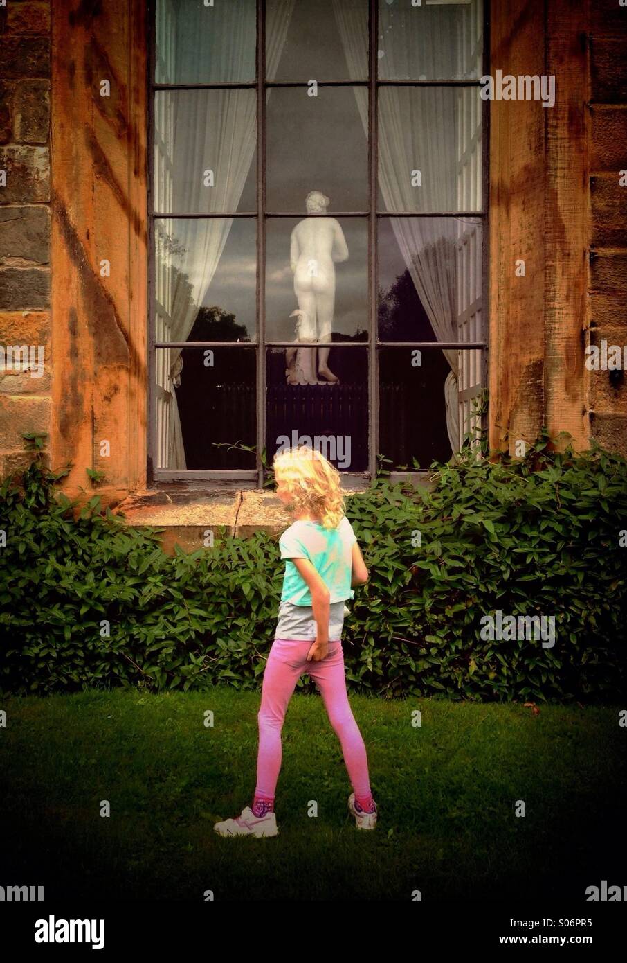 Young girl scratching her bottom looking at the bottom of a sculpture ...