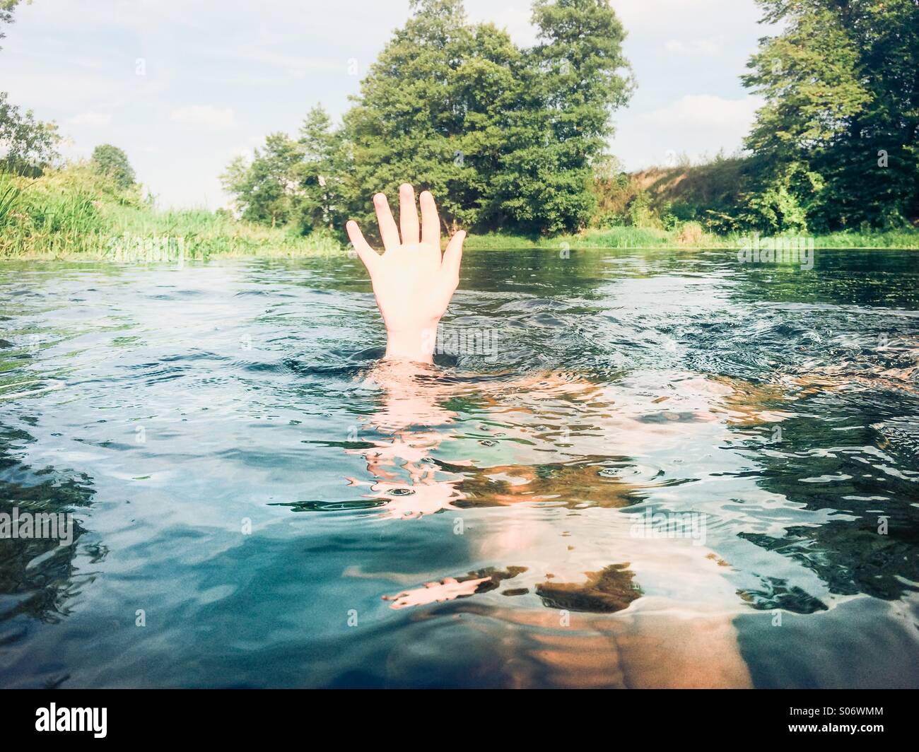 Boy submerged in a pure river keeping his hand above the water Stock ...