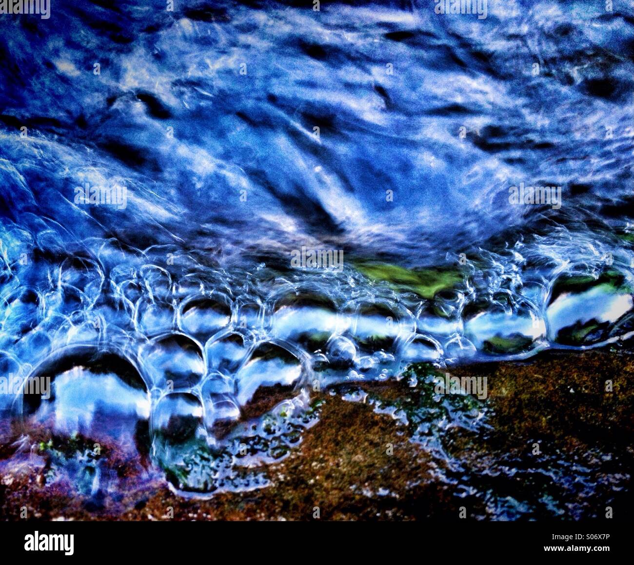Bubbles in fast flowing stream Stock Photo - Alamy