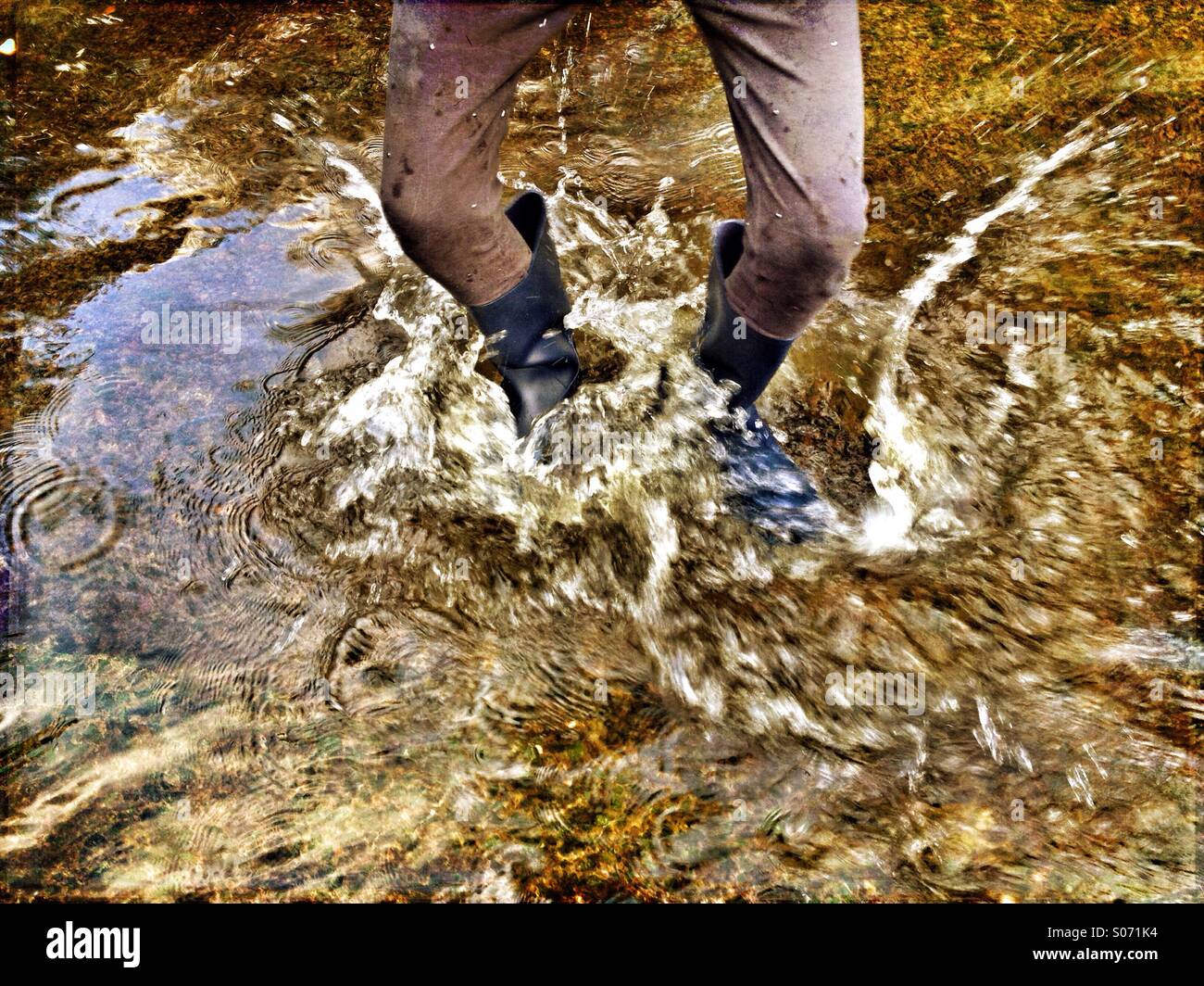 Child splashing in stream with wellies on Stock Photo - Alamy