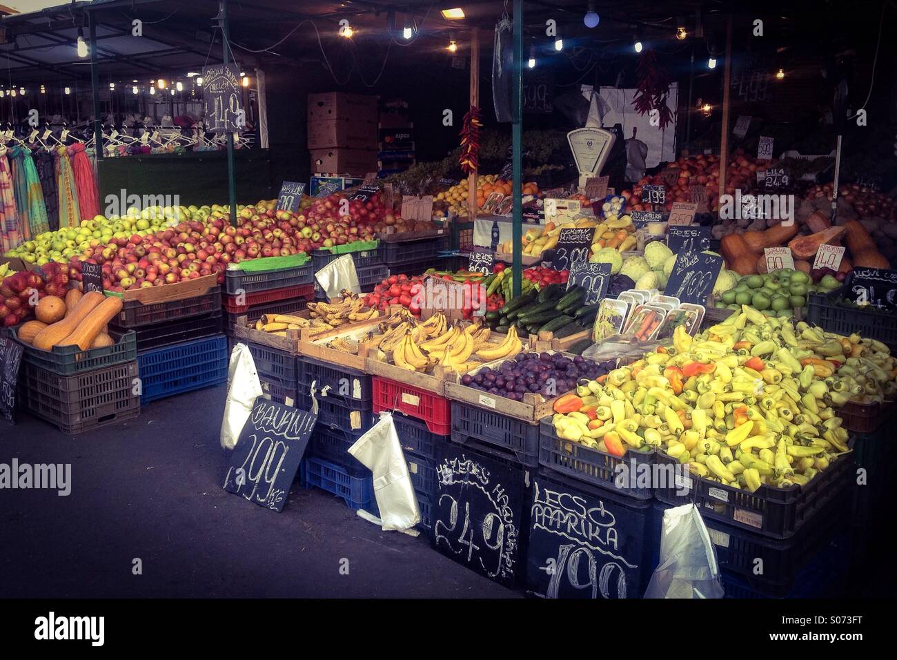 Fresh vegetables and fruits piled up for display on outdoor tables at a ...