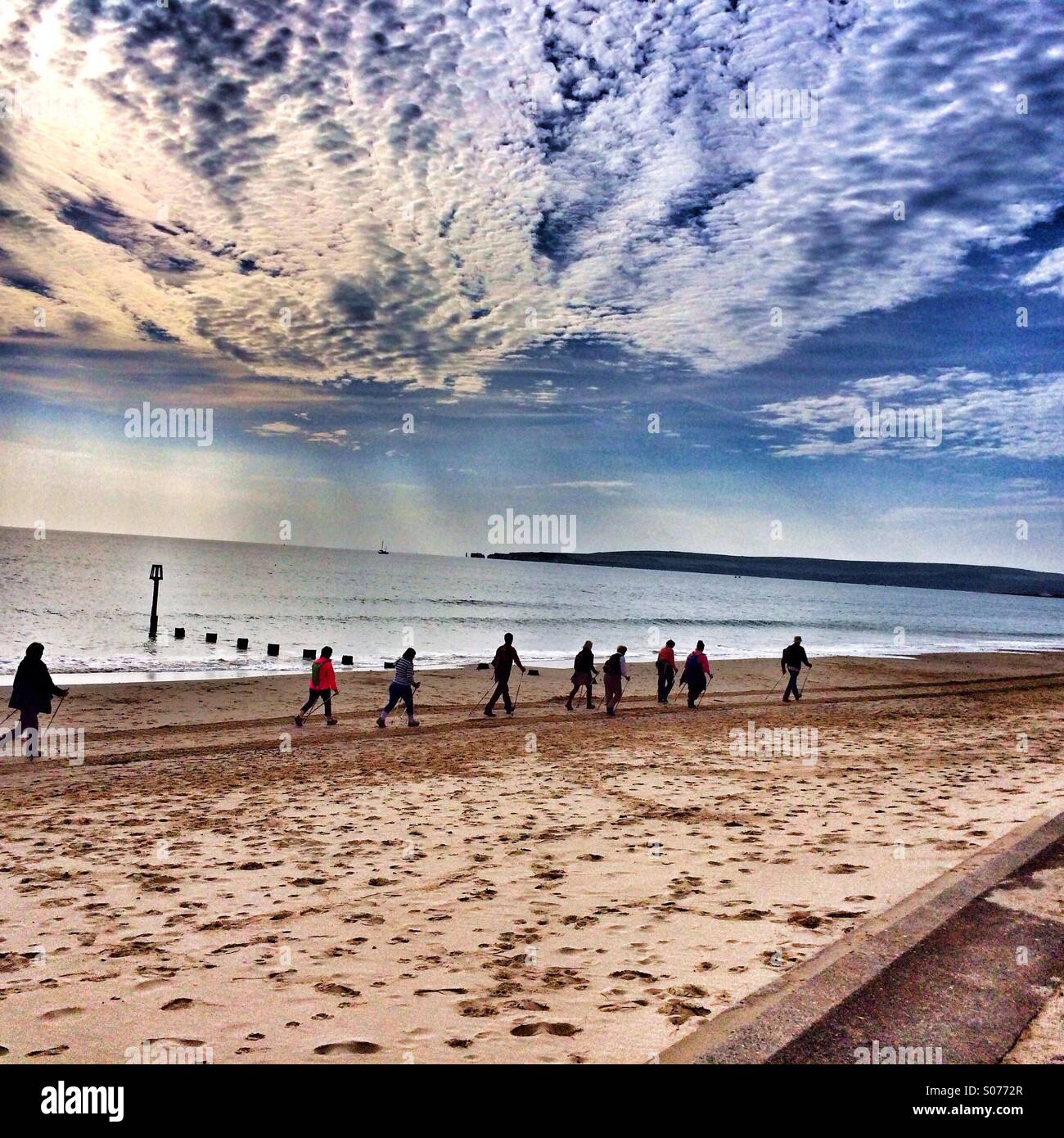 Group of walkers walking along beach Stock Photo - Alamy