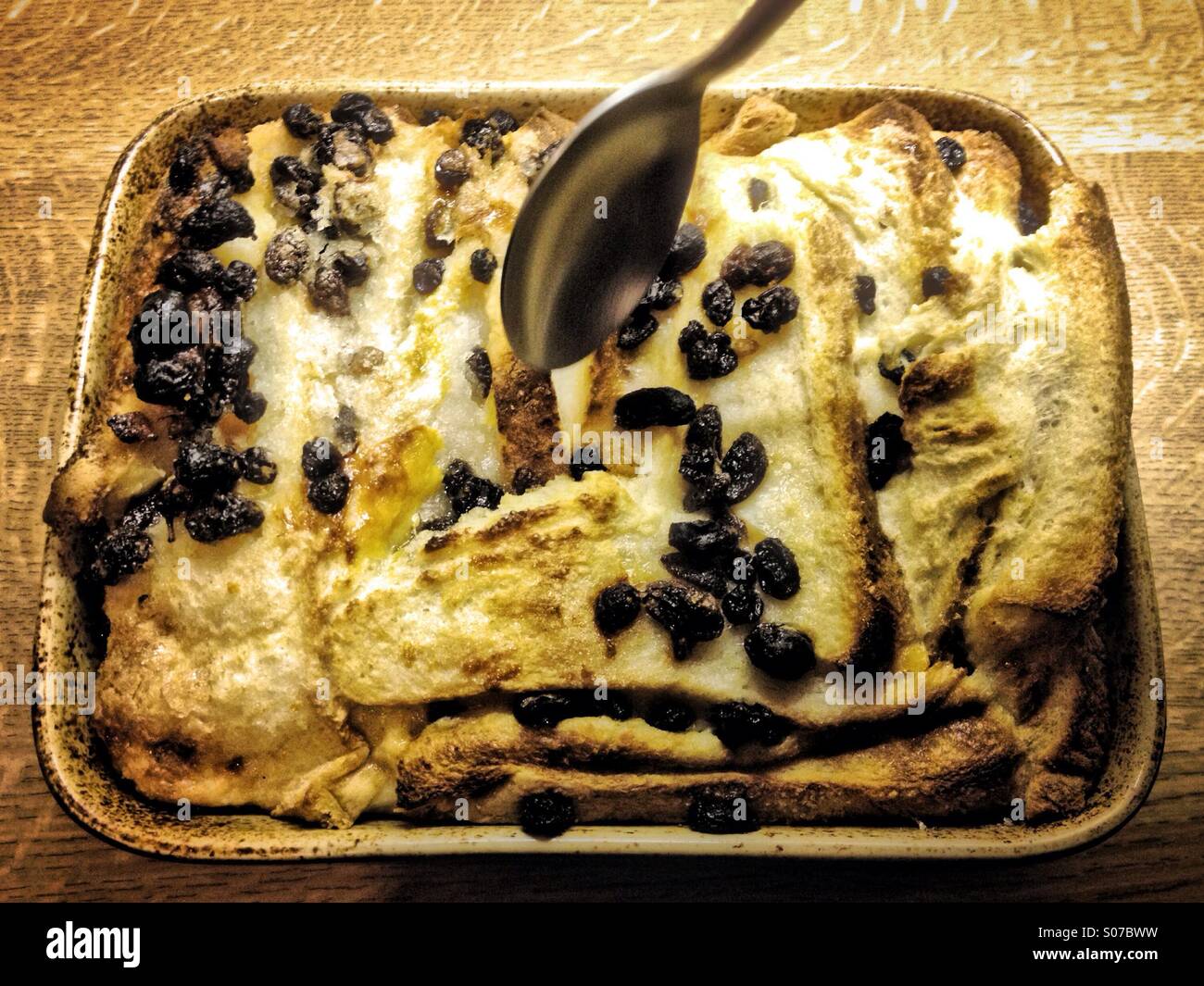 Putting a spoon into bread and butter pudding Stock Photo - Alamy