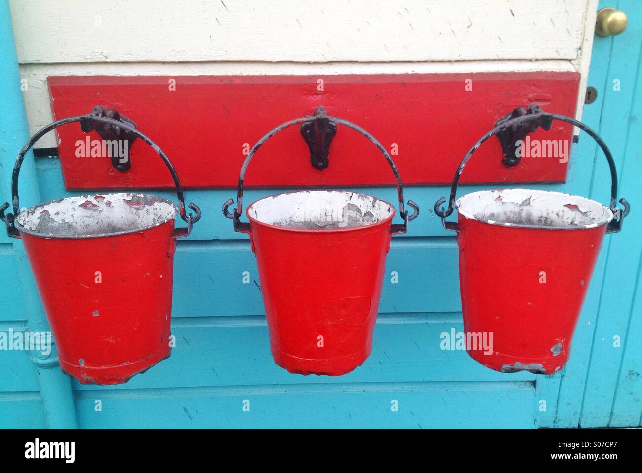 Three red fire buckets against blue wall Stock Photo - Alamy