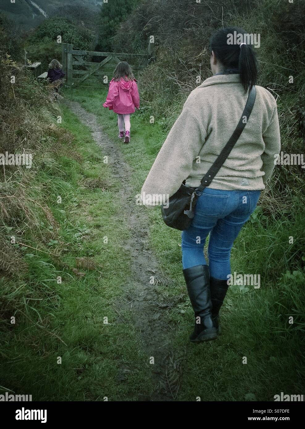 Family walk. A mother's young daughters lead the way along a country ...