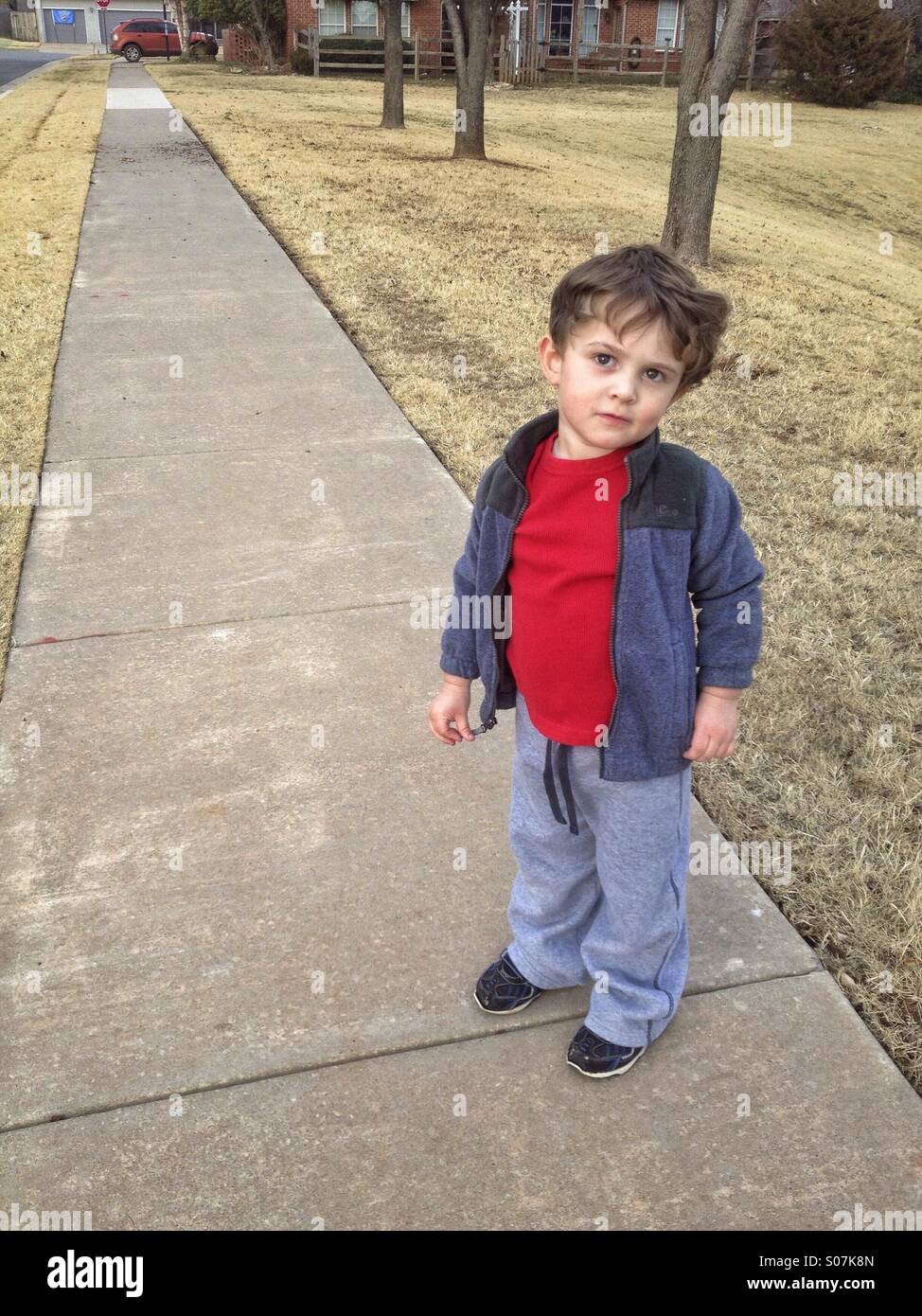 Questioning look of a little boy on a sidewalk outside Stock Photo - Alamy