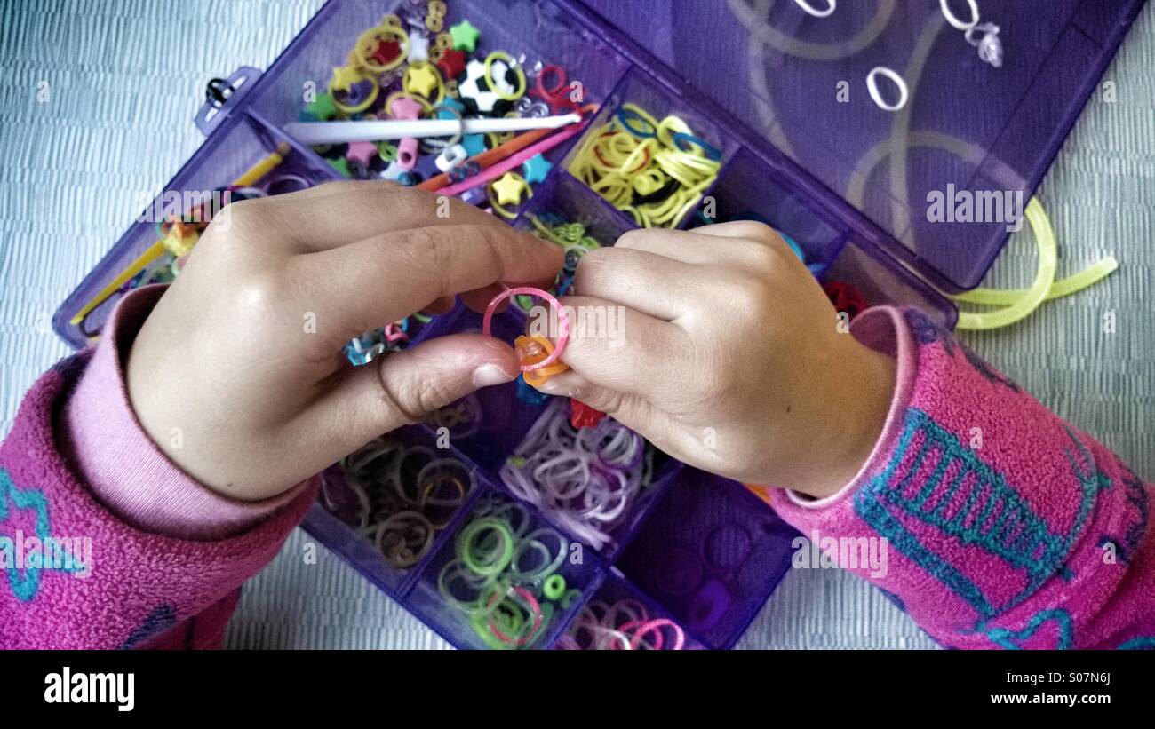Young girl making something with loom bands. POV image of hands loom ...