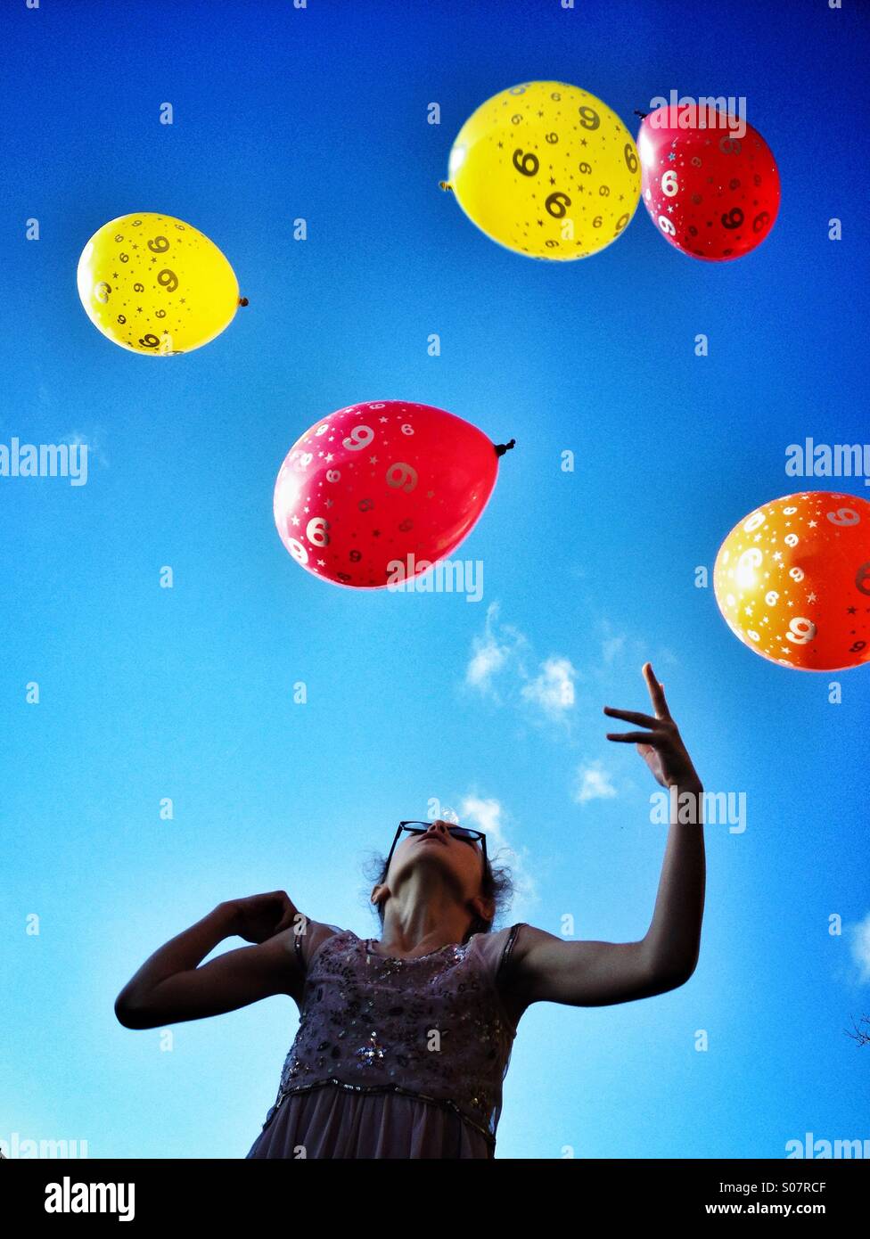 Young girl throwing party balloons in to air Stock Photo - Alamy