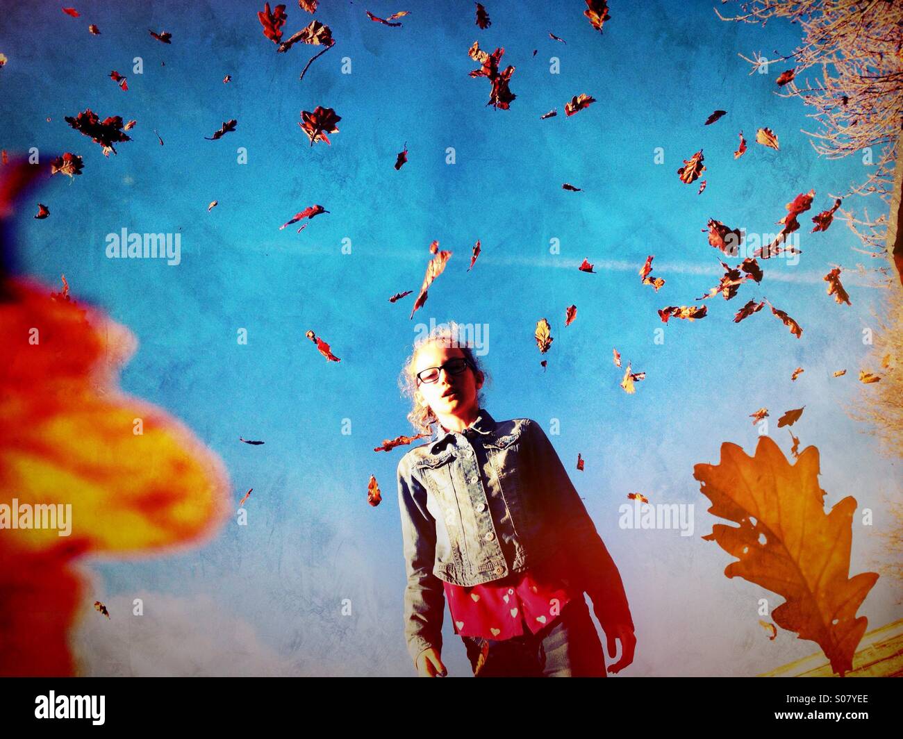Autumn leaves falling around young girl Stock Photo - Alamy
