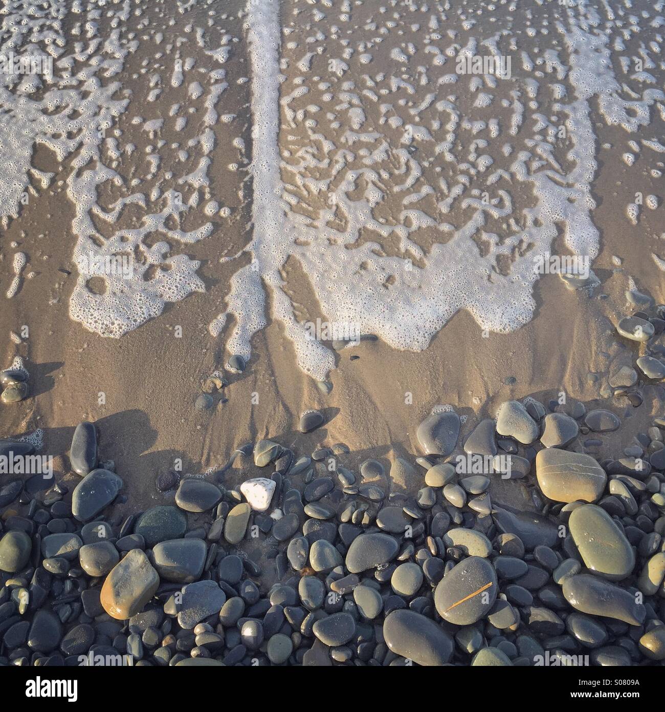 Shoreline, pebbles, sand and wave, Wales Stock Photo - Alamy