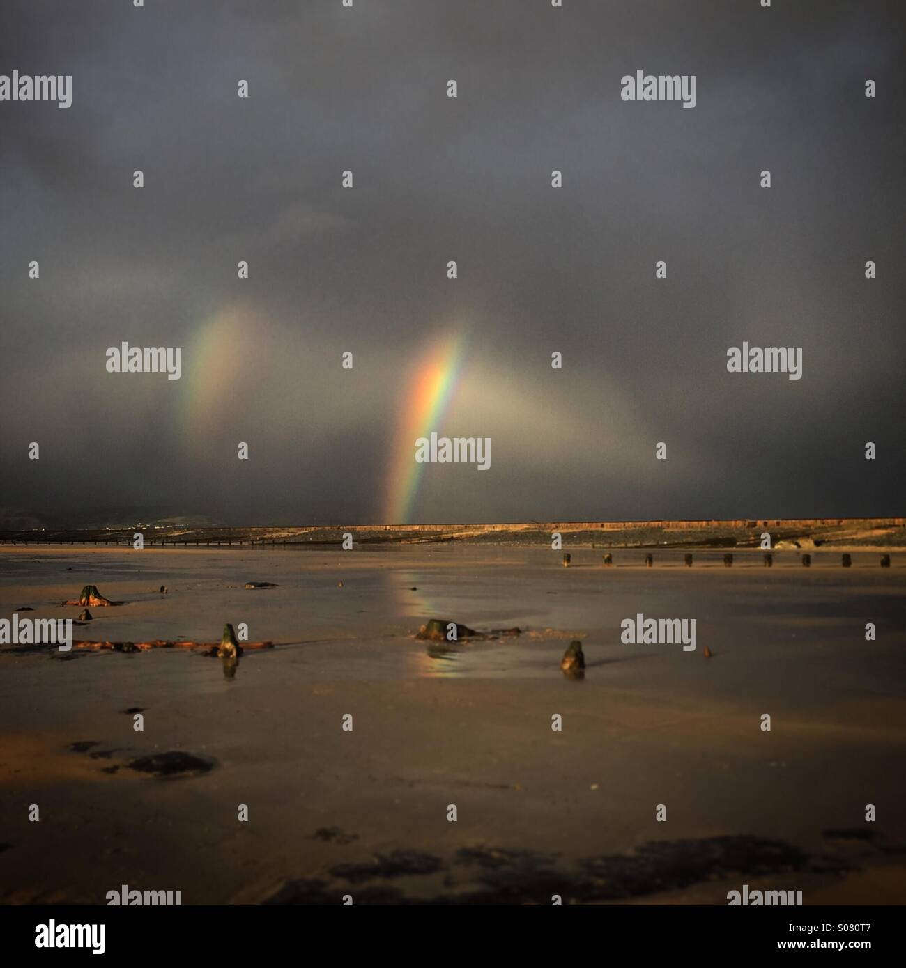 Rainbow over beach,dramatic sky Stock Photo - Alamy