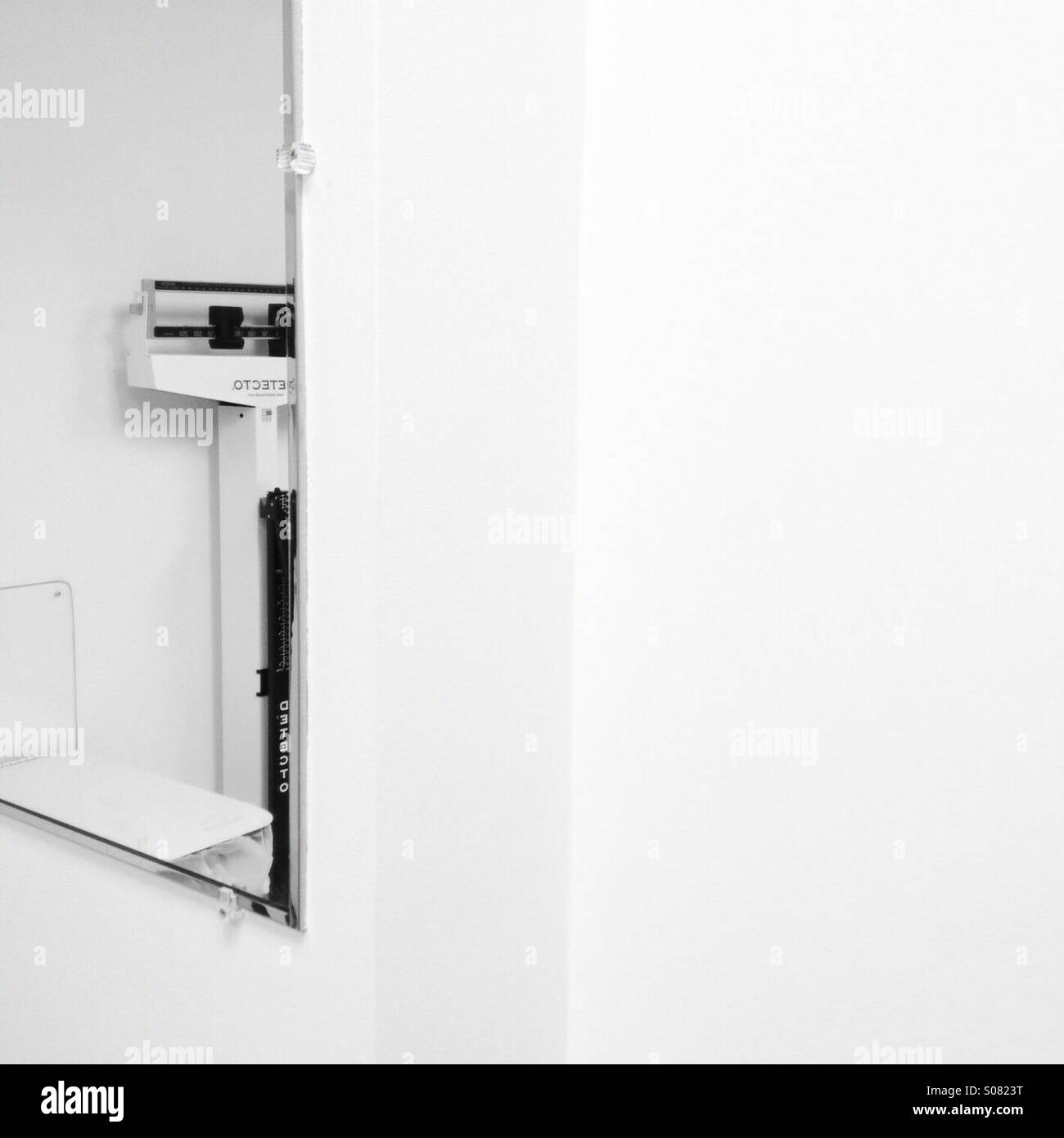 Scale reflected in a mirror in a white room Stock Photo - Alamy