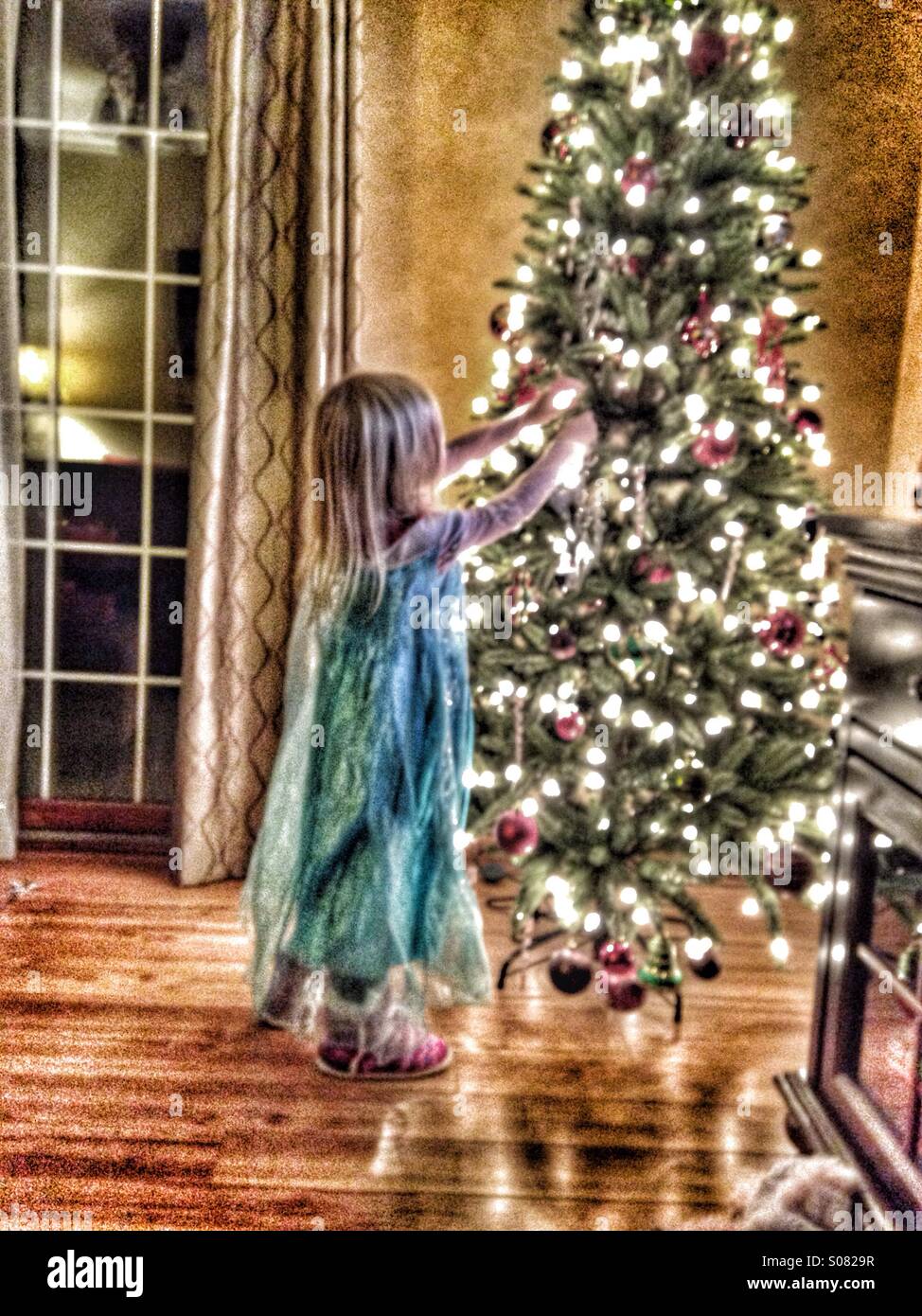 A little princess decorating the Christmas tree Stock Photo - Alamy