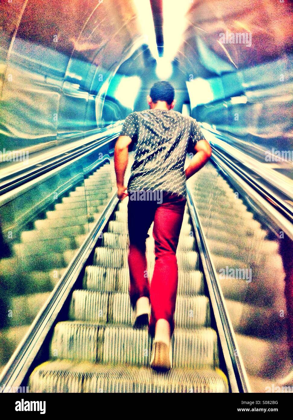 Young man rushing up escalator Stock Photo - Alamy