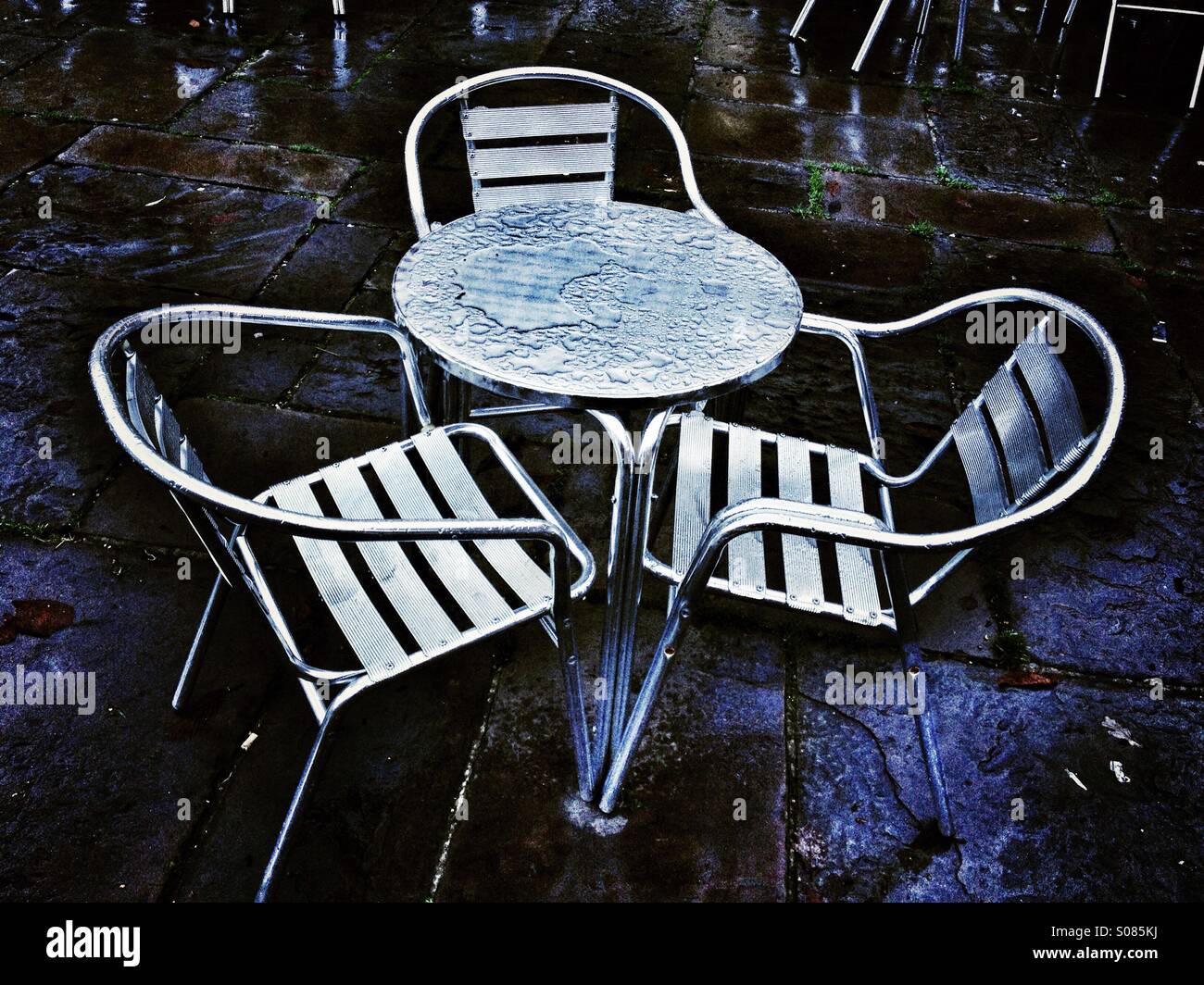 Metal table and chairs in the rain Stock Photo - Alamy