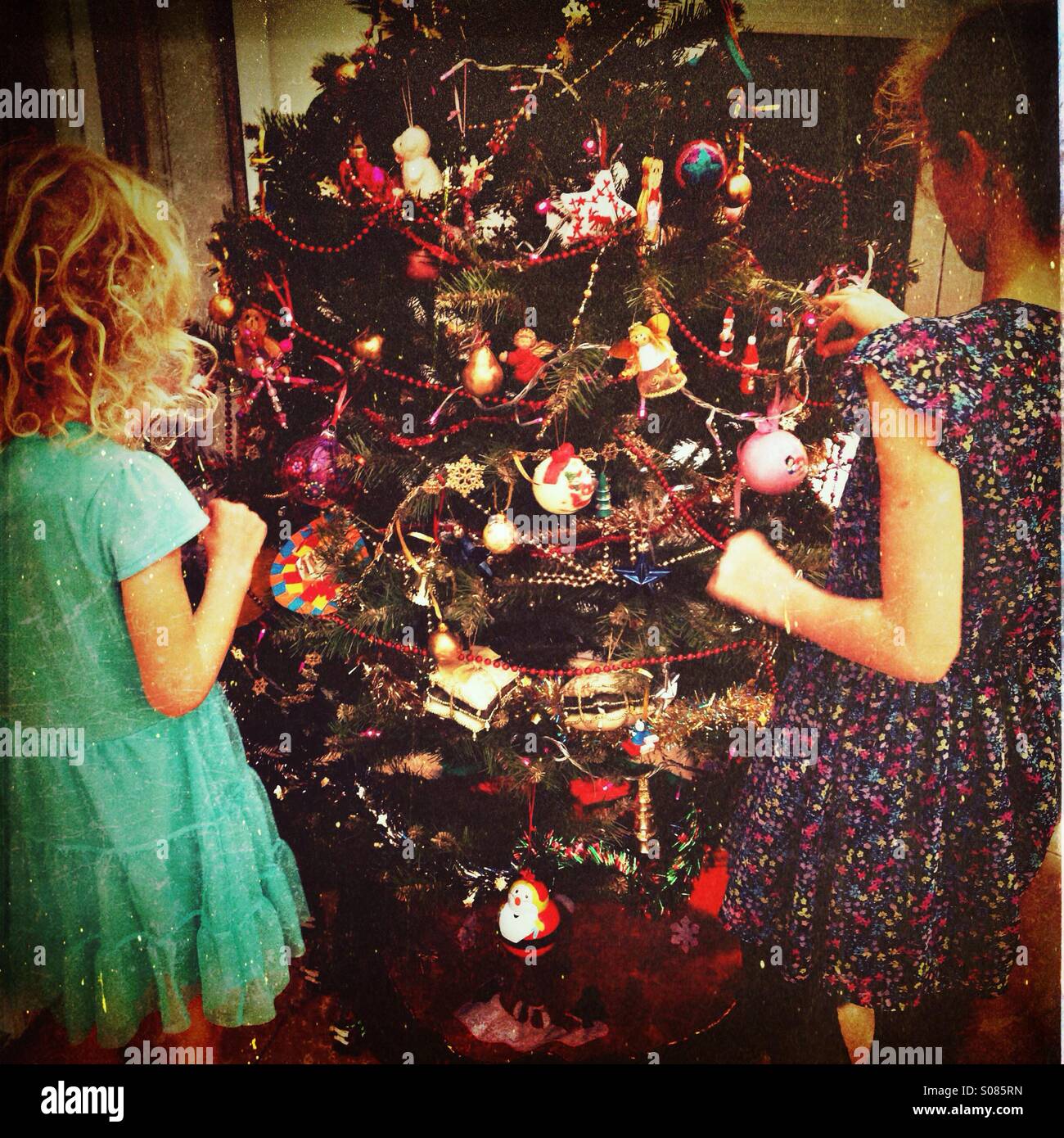 Two children putting decorations on Christmas tree Stock Photo - Alamy