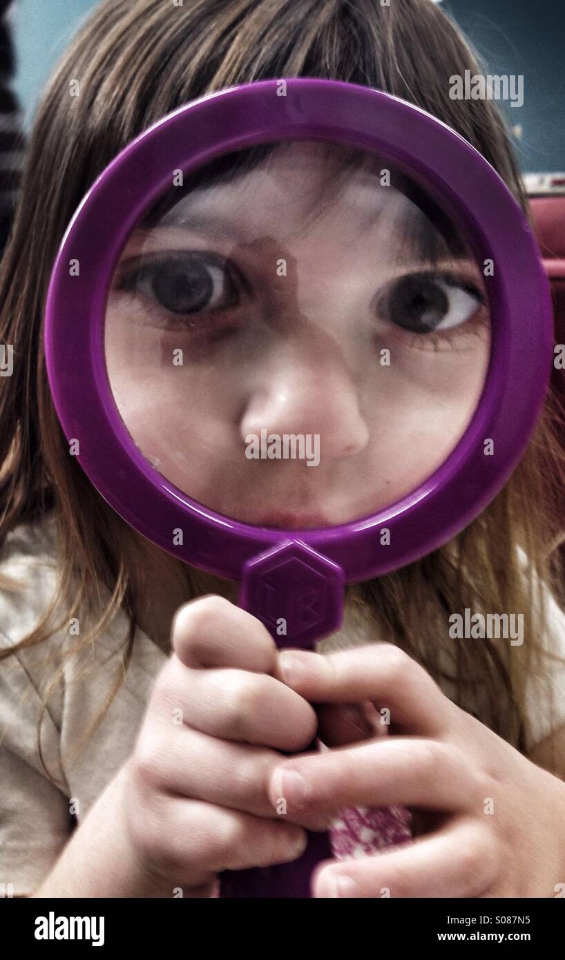 Toddler girl looking through magnifying glass Stock Photo - Alamy