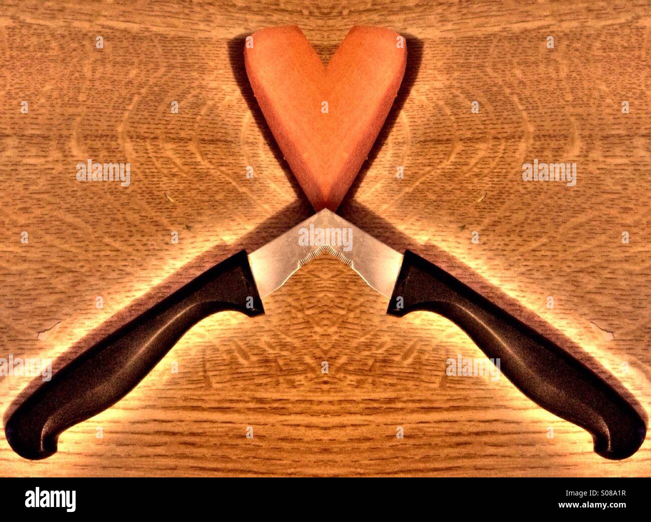 Symmetrical photo of a knife cutting carrots which form a love heart ...