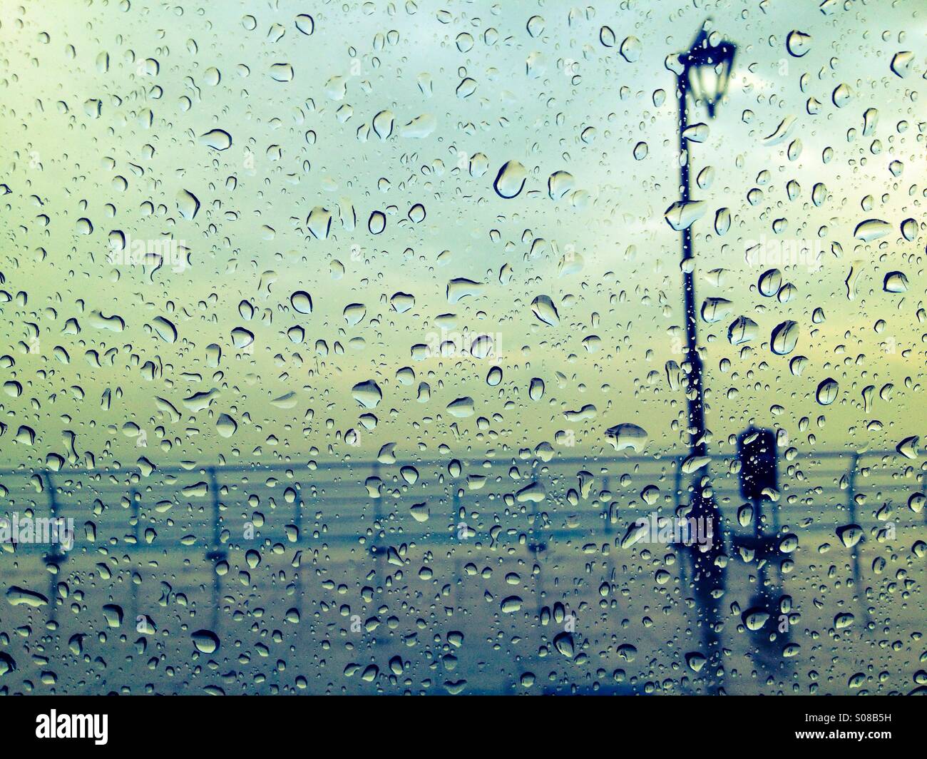 Watching water drops behind a window glass in winter at the promenade ...