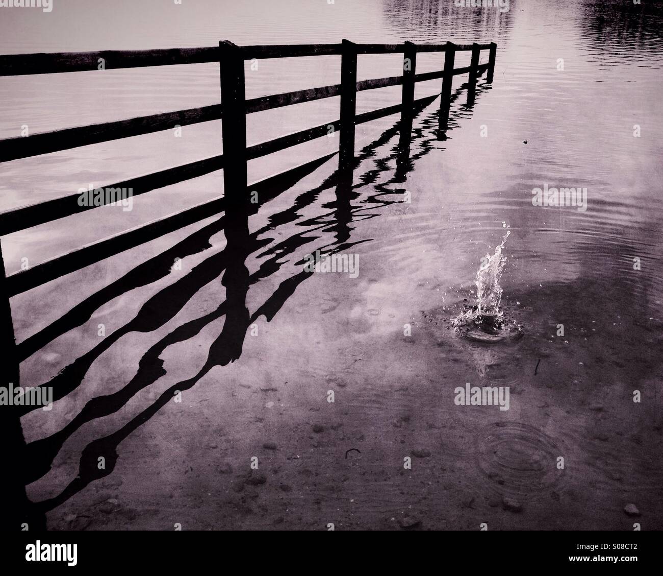 Reflection of fence in water balanced by splash Stock Photo - Alamy