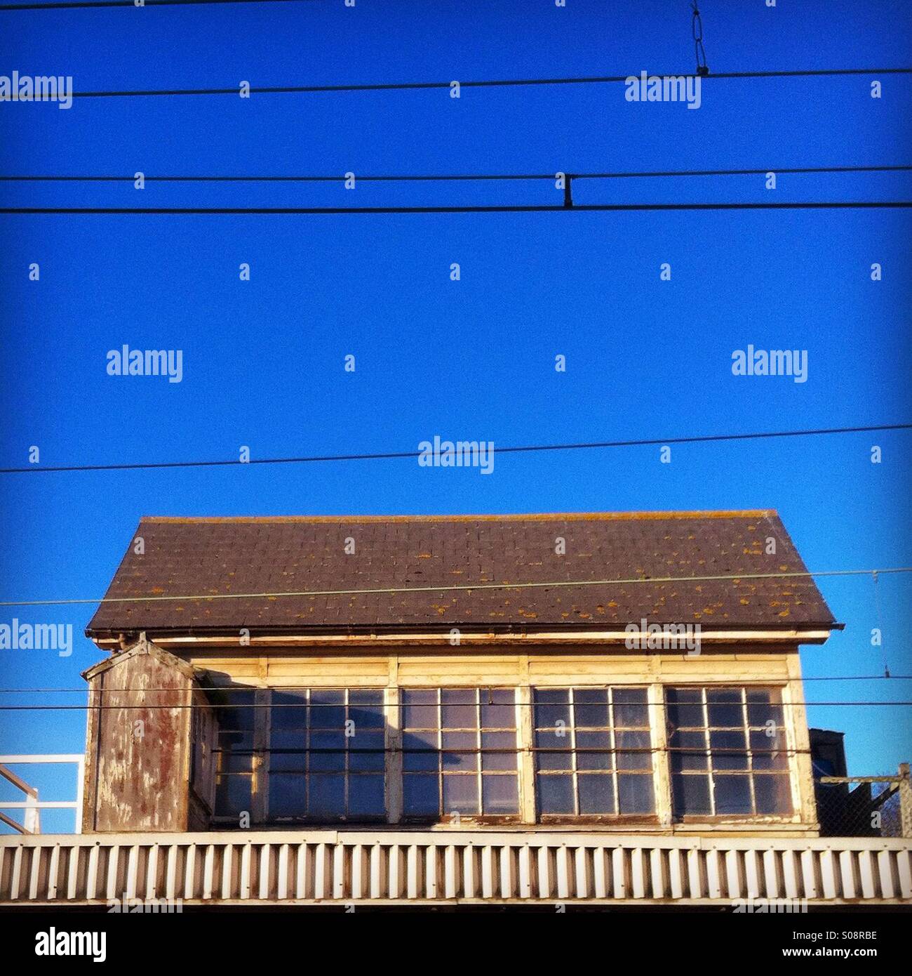Abandoned hut with deep blue sky behind and train power lines above ...