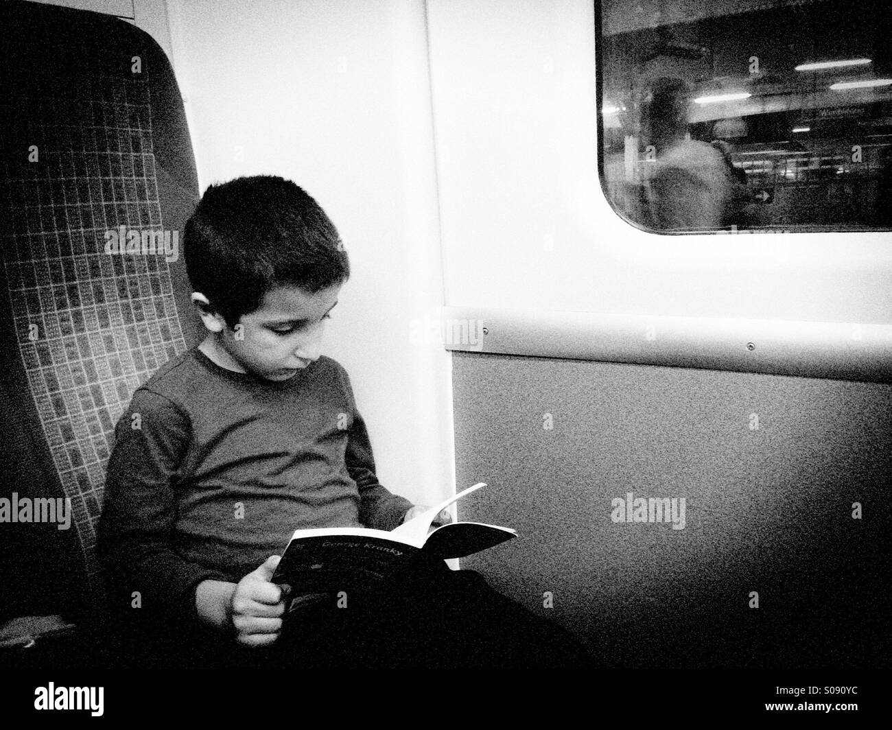 Boy reading book on the train Stock Photo - Alamy