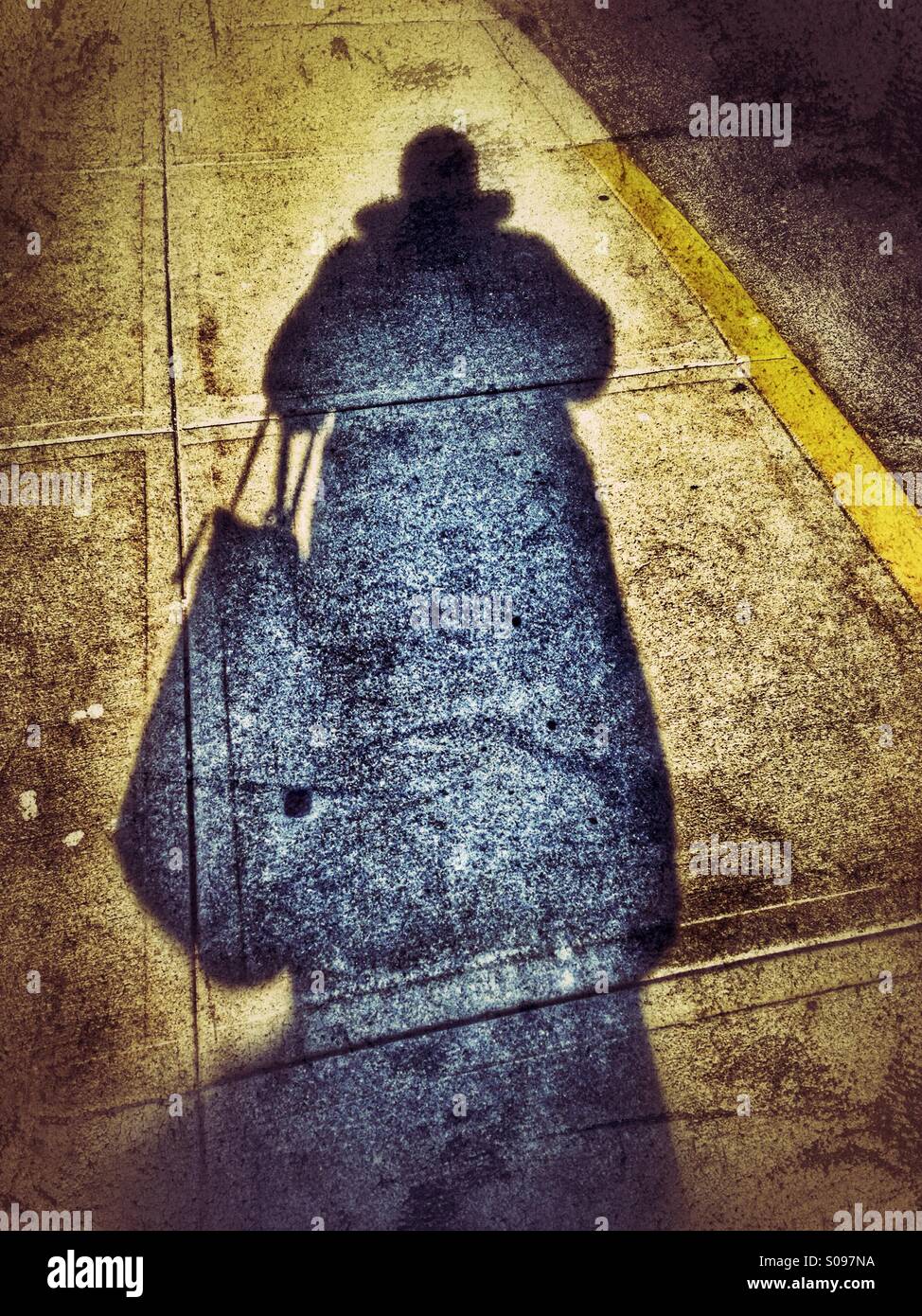 A winter coat wearing, large bag carrying shadow on the sidewalk Stock ...