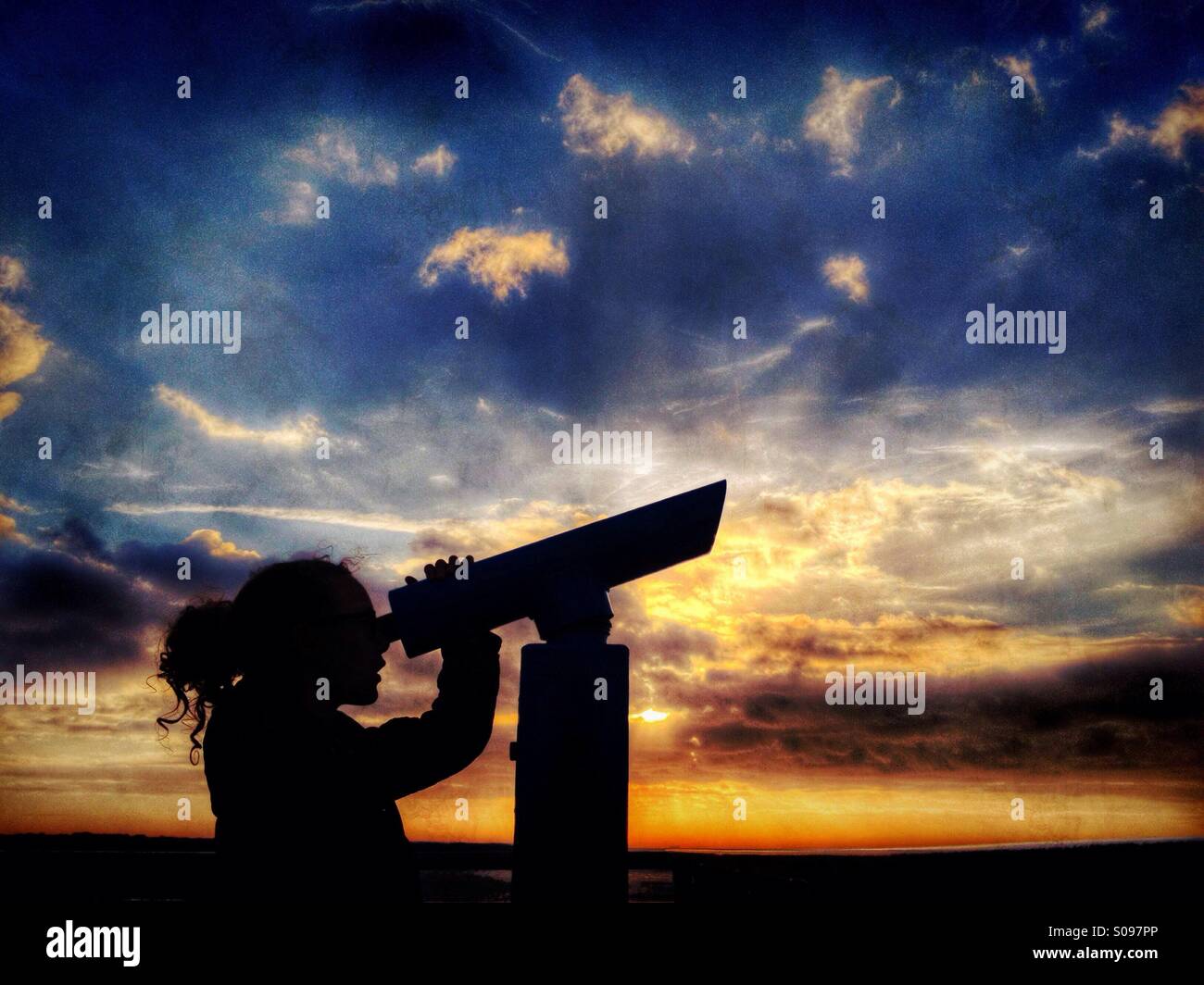 Girl gazing through telescope at sunset Stock Photo - Alamy
