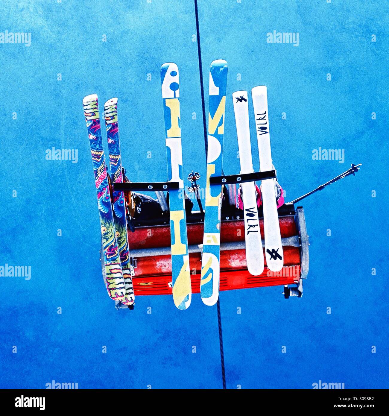 Three skiers riding a chairlift to the top of the mountain viewed from ...