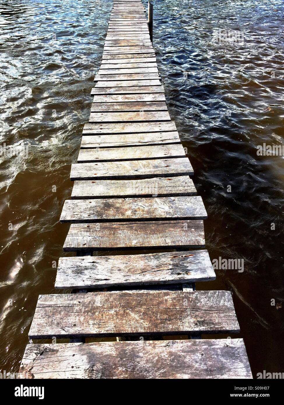 Rickety dock across water Stock Photo - Alamy
